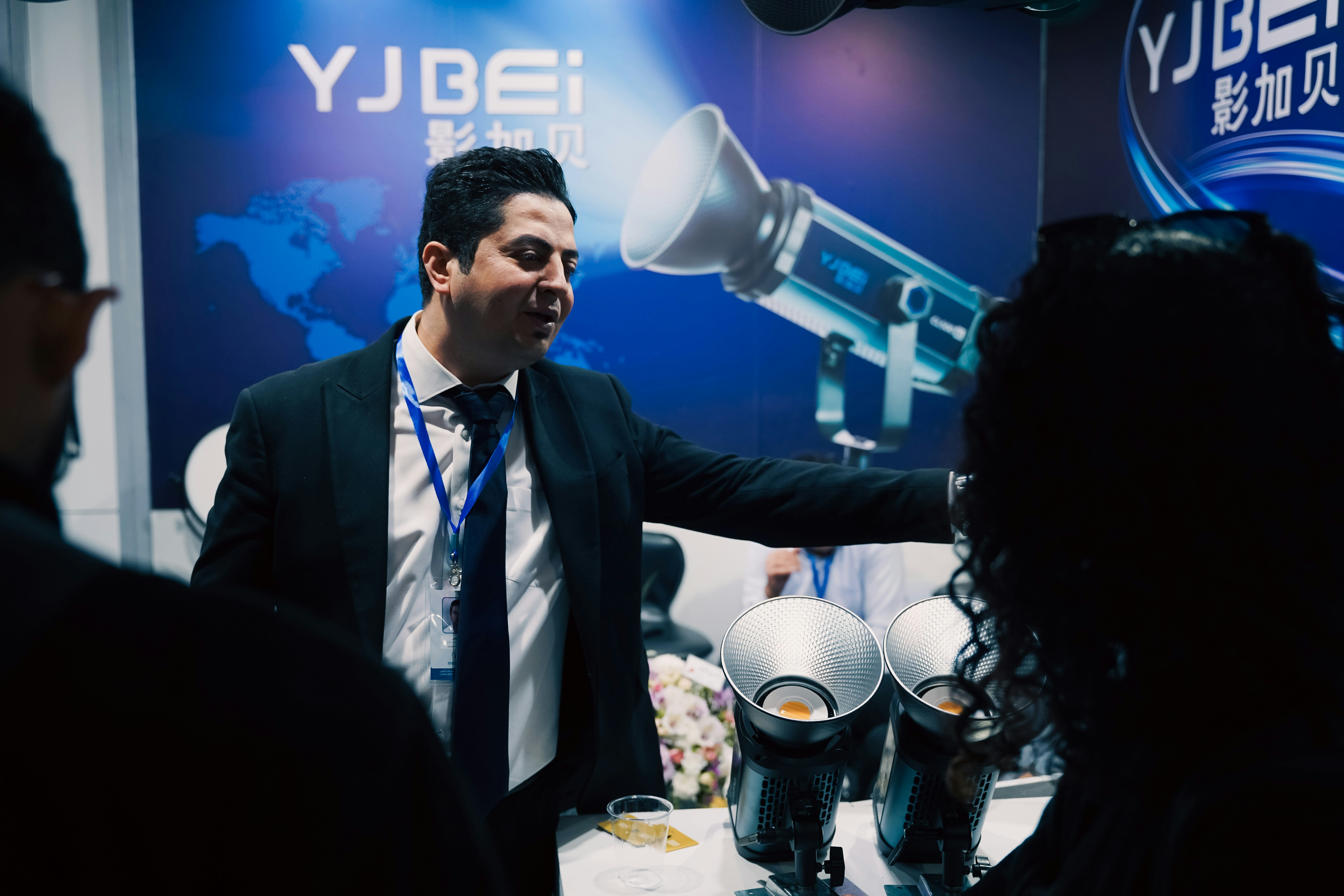 A professional engaging with attendees while showcasing advanced lighting equipment at an exhibition booth.