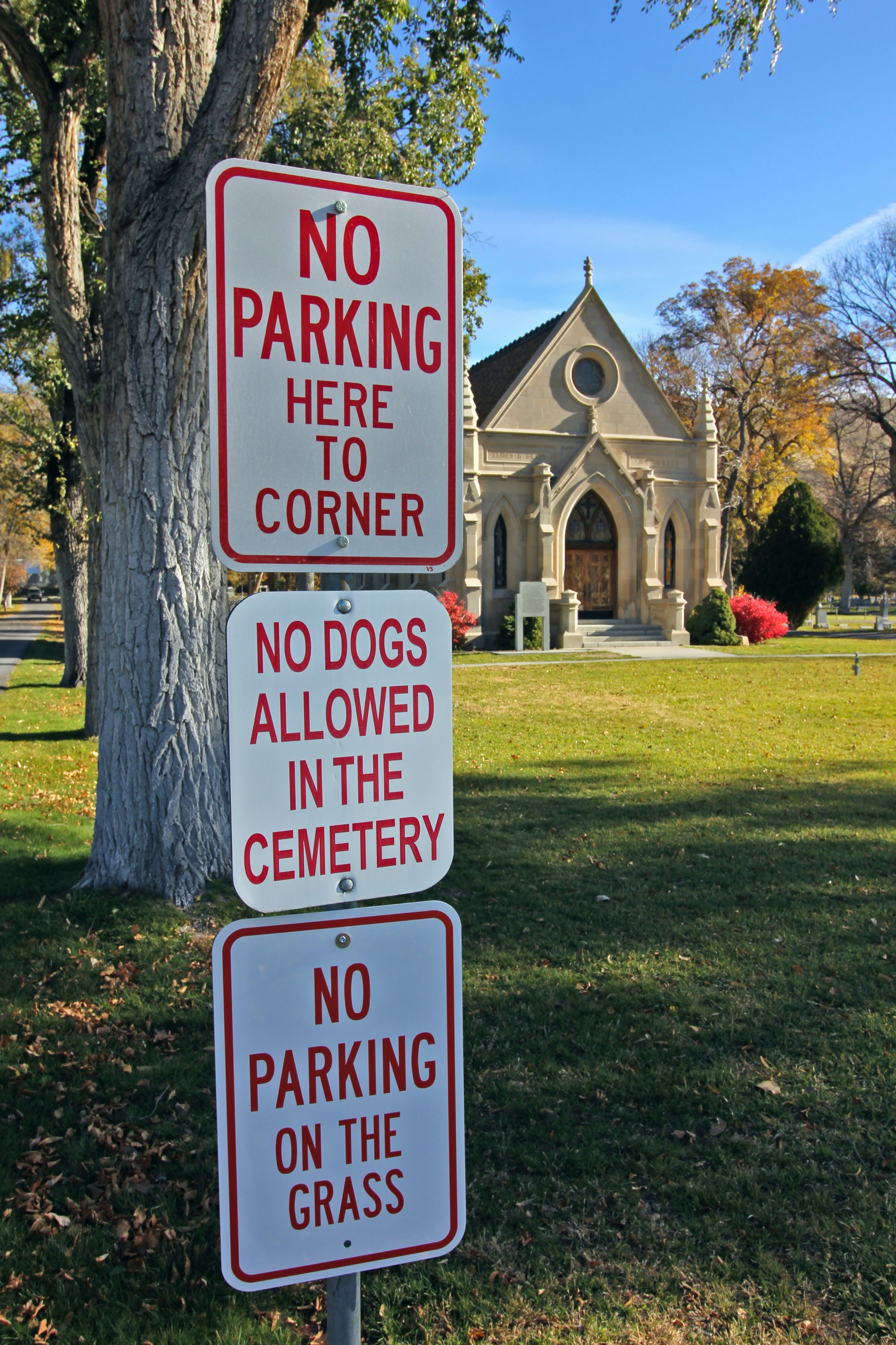 Vertical Signpost Chorus Framing a Quiet Cemetery Chapel in Autumn Light