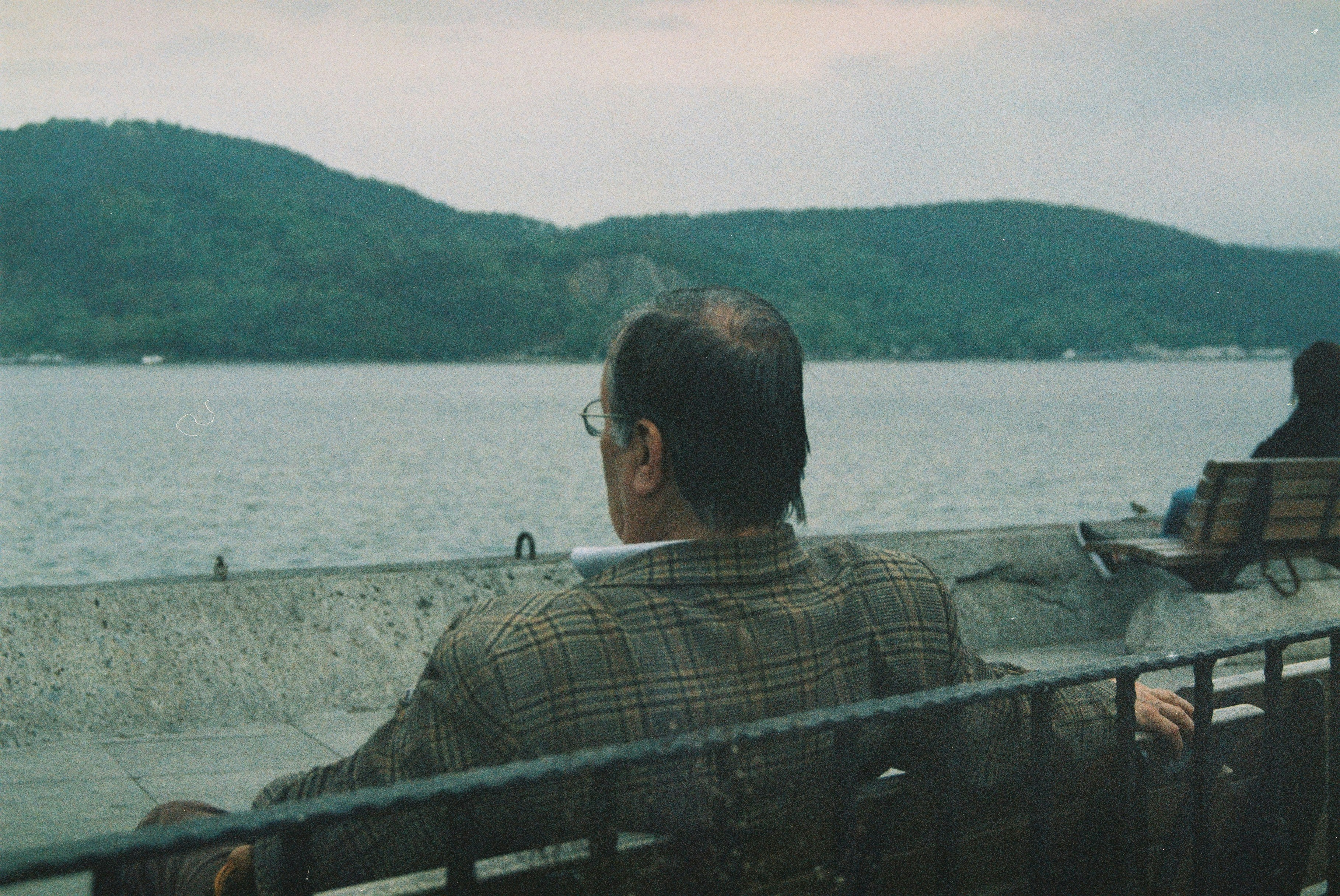 A Quiet Moment by the Waterfront: Man in Plaid Overlooks the Sea