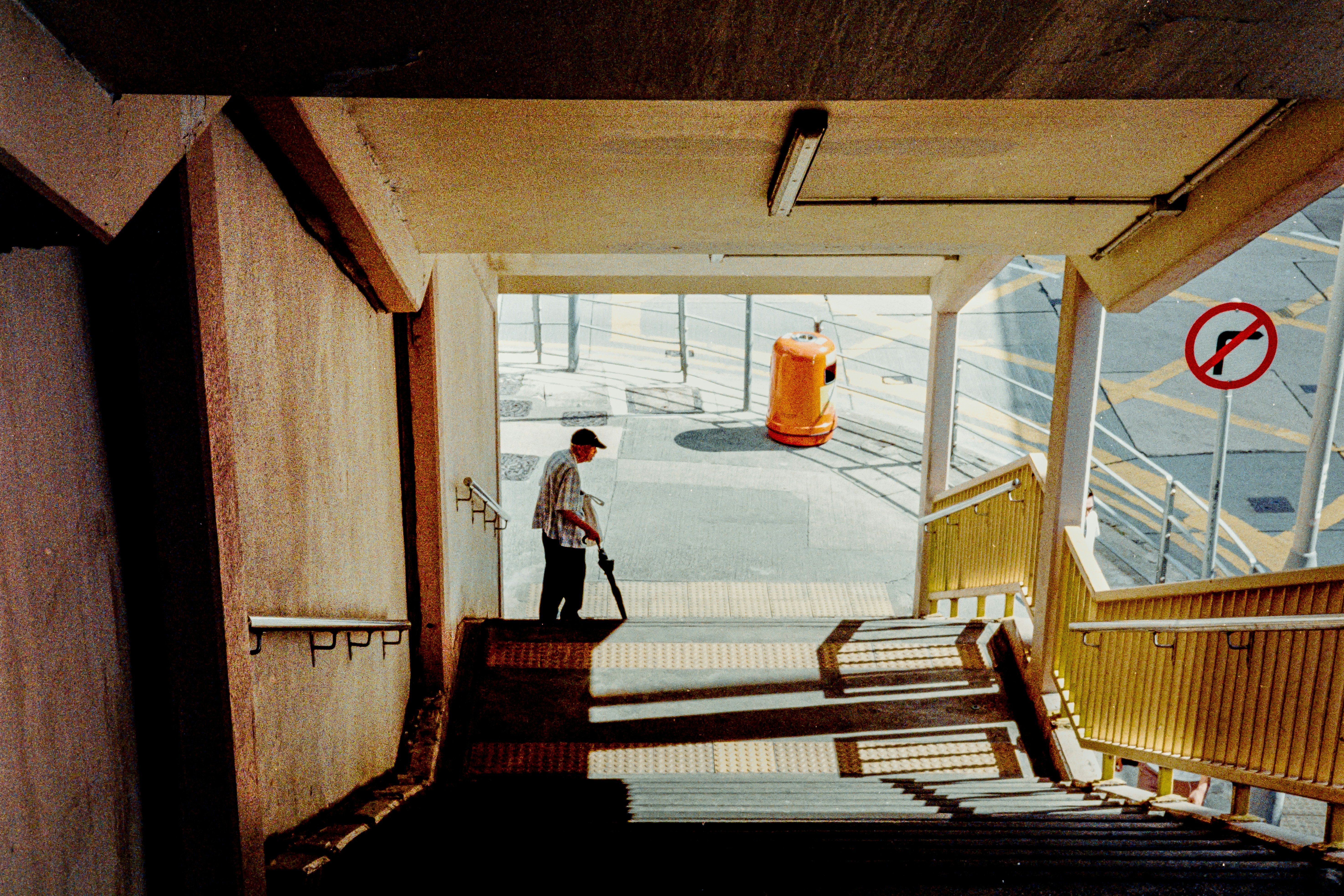 Man with umbrella walks down concrete stairs