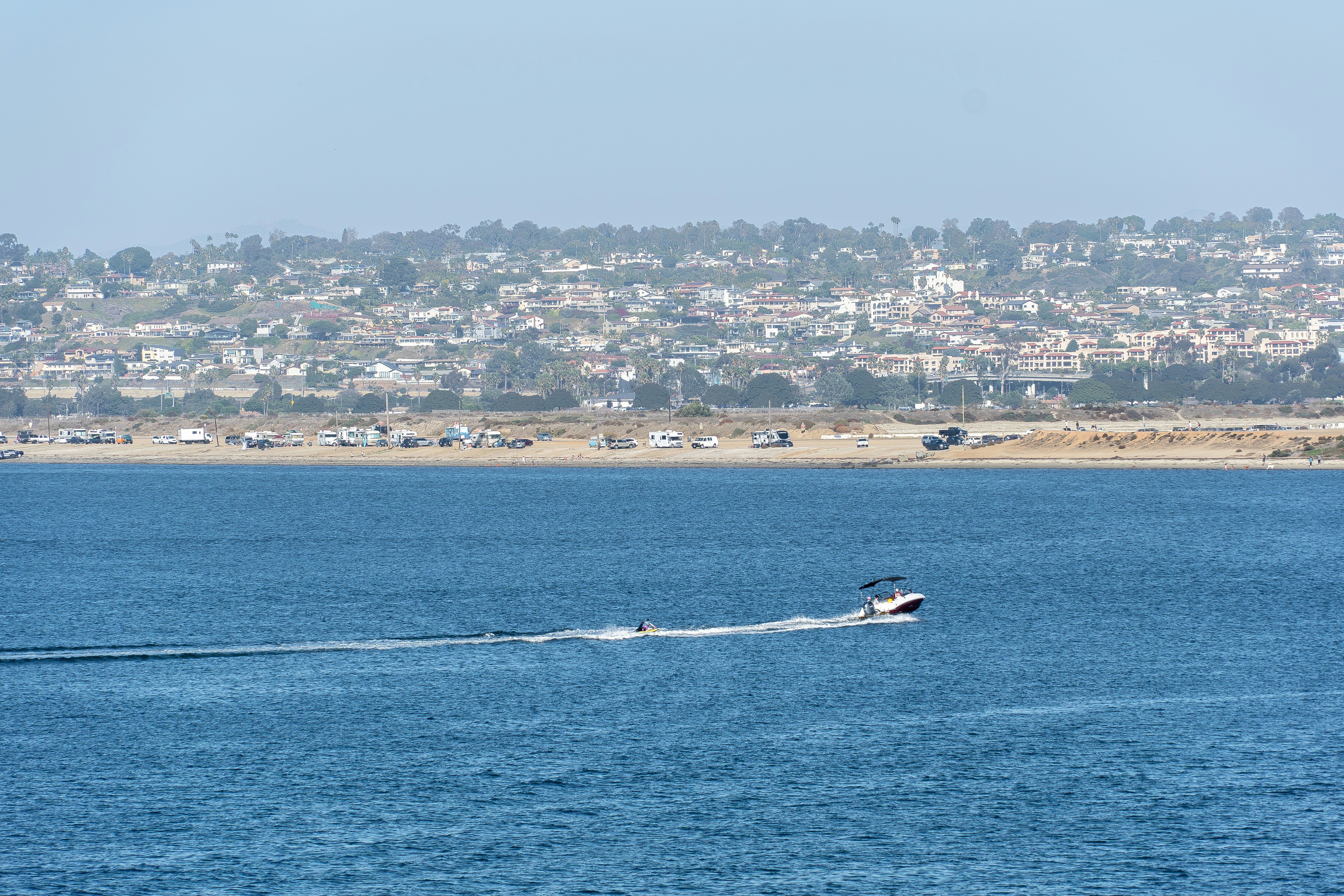 White Wake Across Blue Horizon: A Speedboat Traces a Line Through Coastal Calm