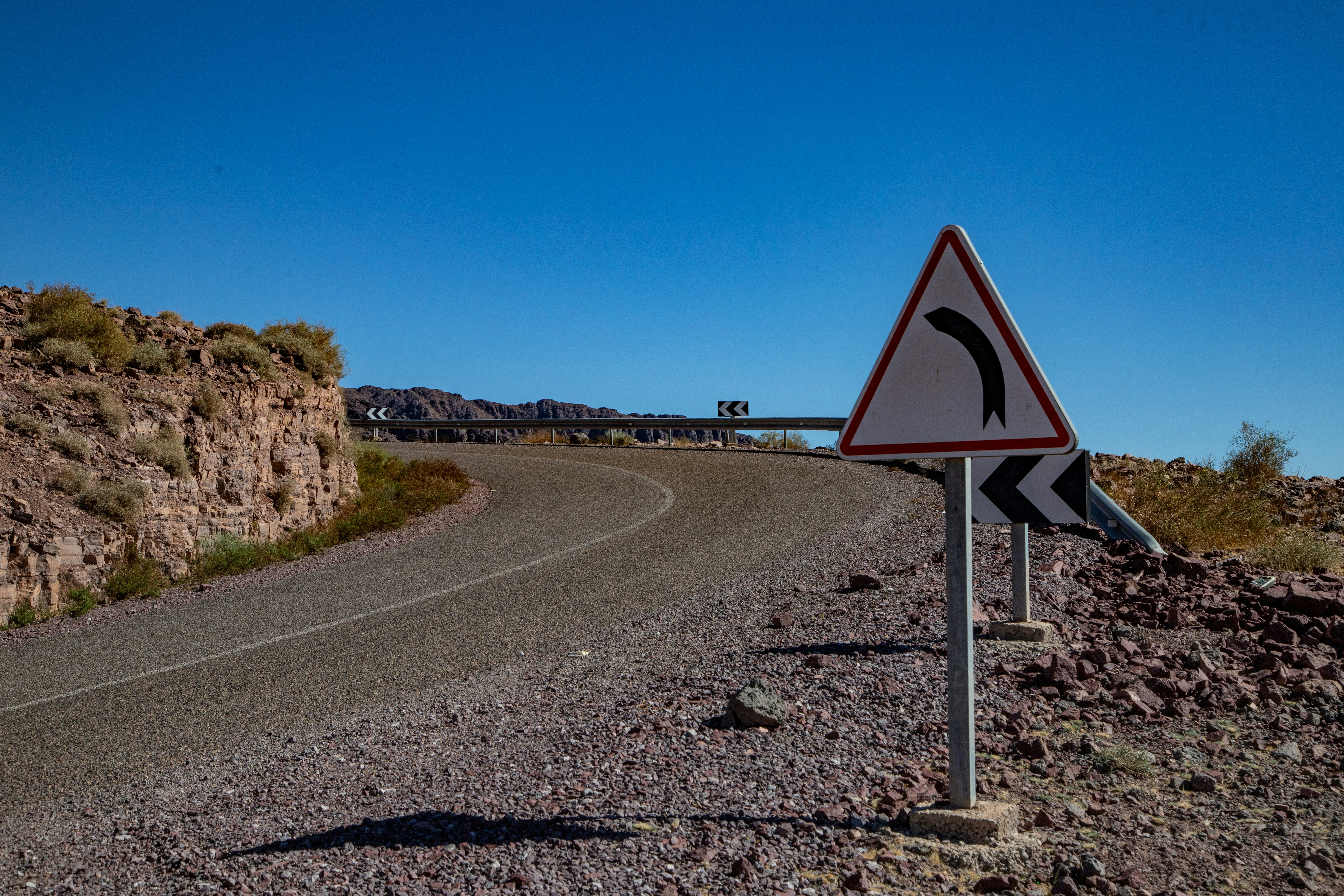 Desert Bend: A Lone Road Sign Framed by Gravel and Sky
