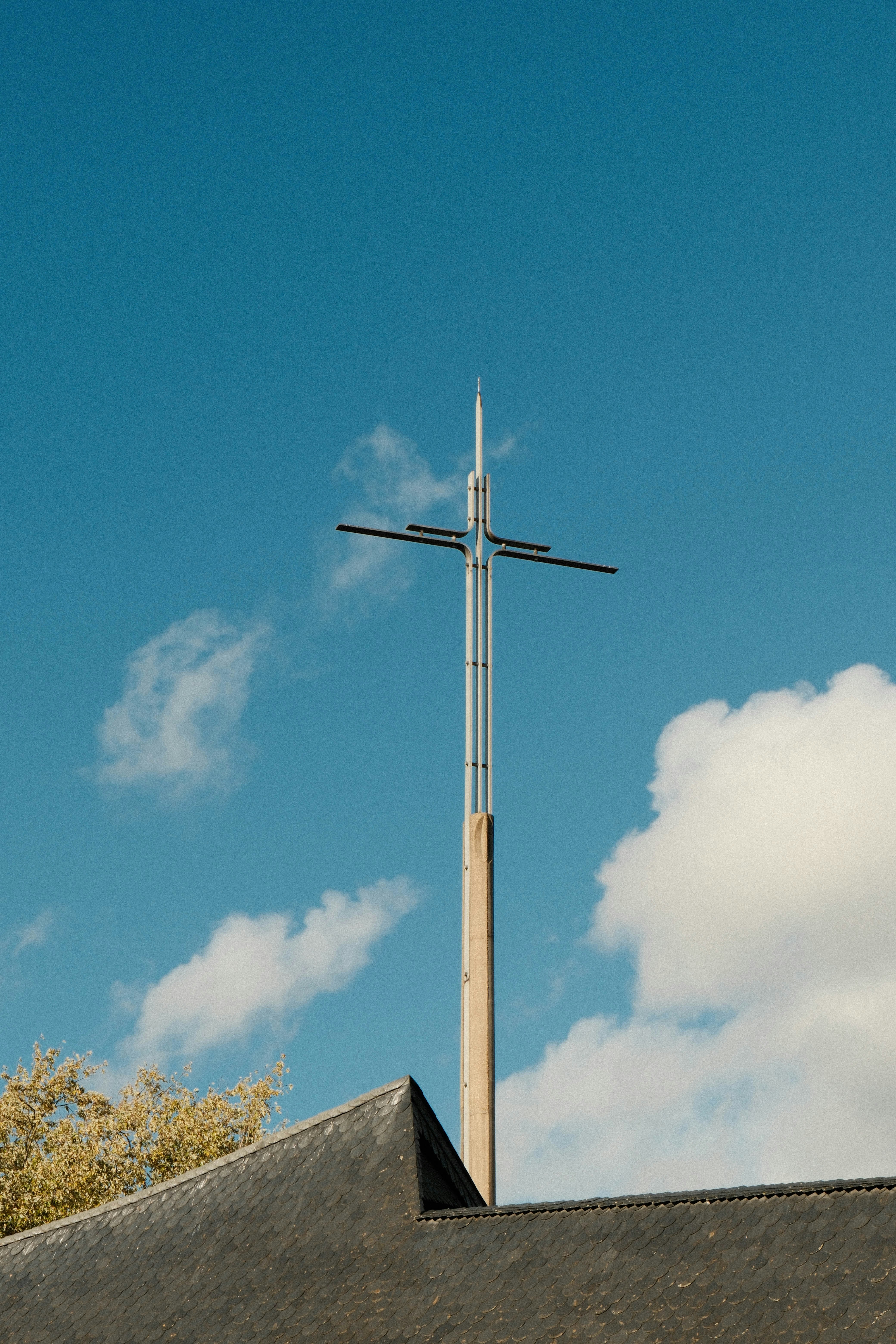A tall cross against a blue sky with clouds