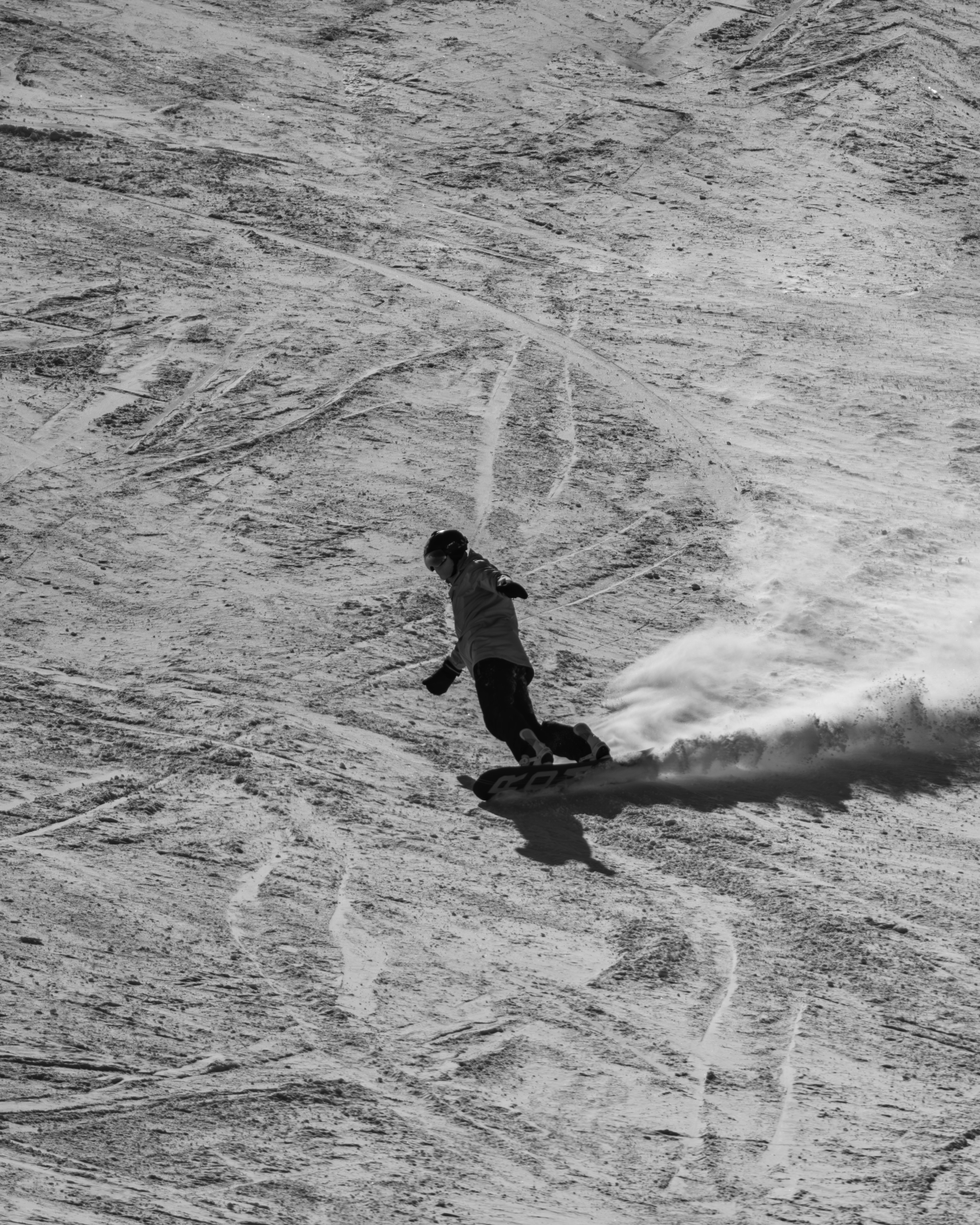 Grayscale Carve: Snowboarder tracing a powder arc down the slope
