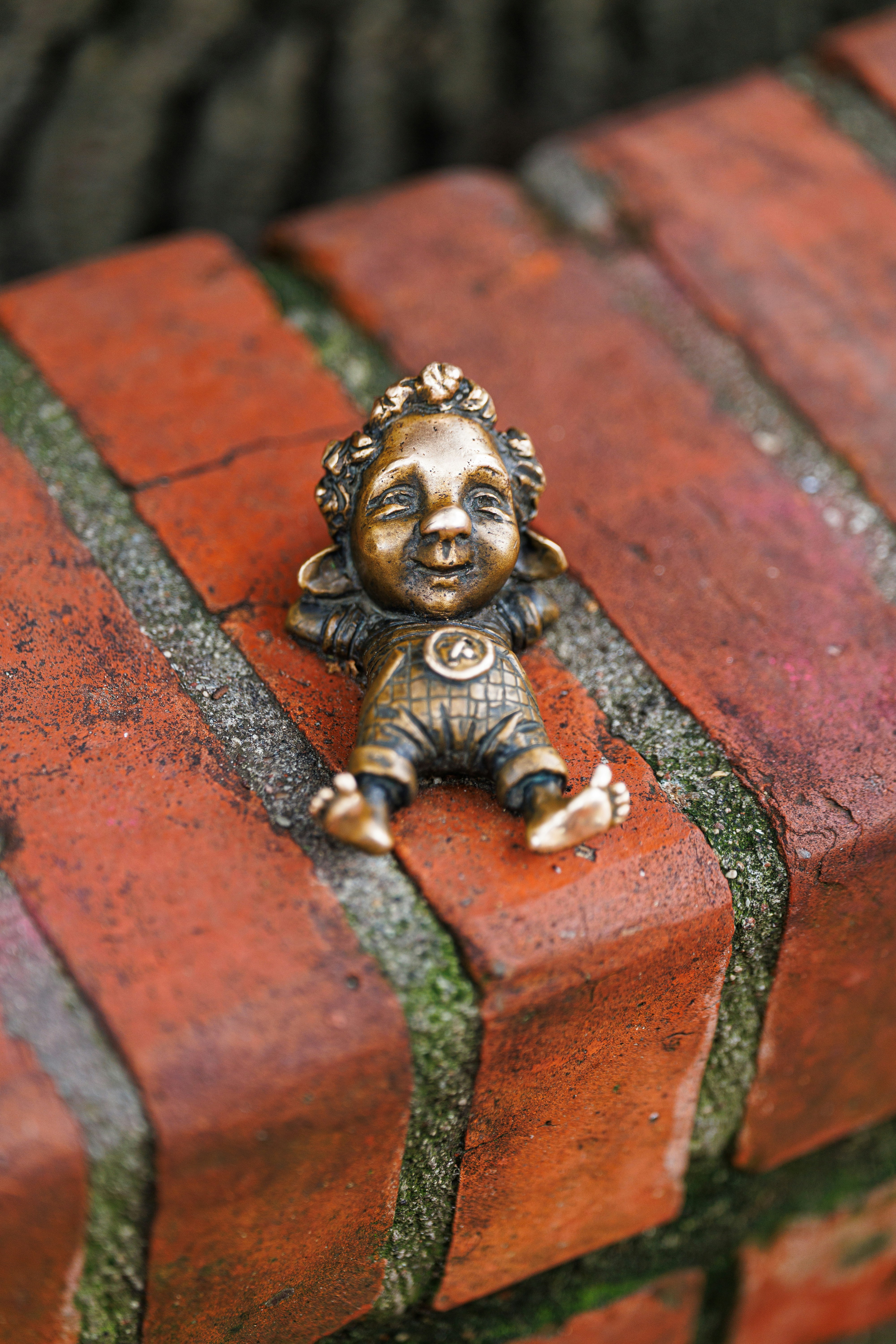 Tiny Bronze Cherub Repose on Weathered Red Bricks