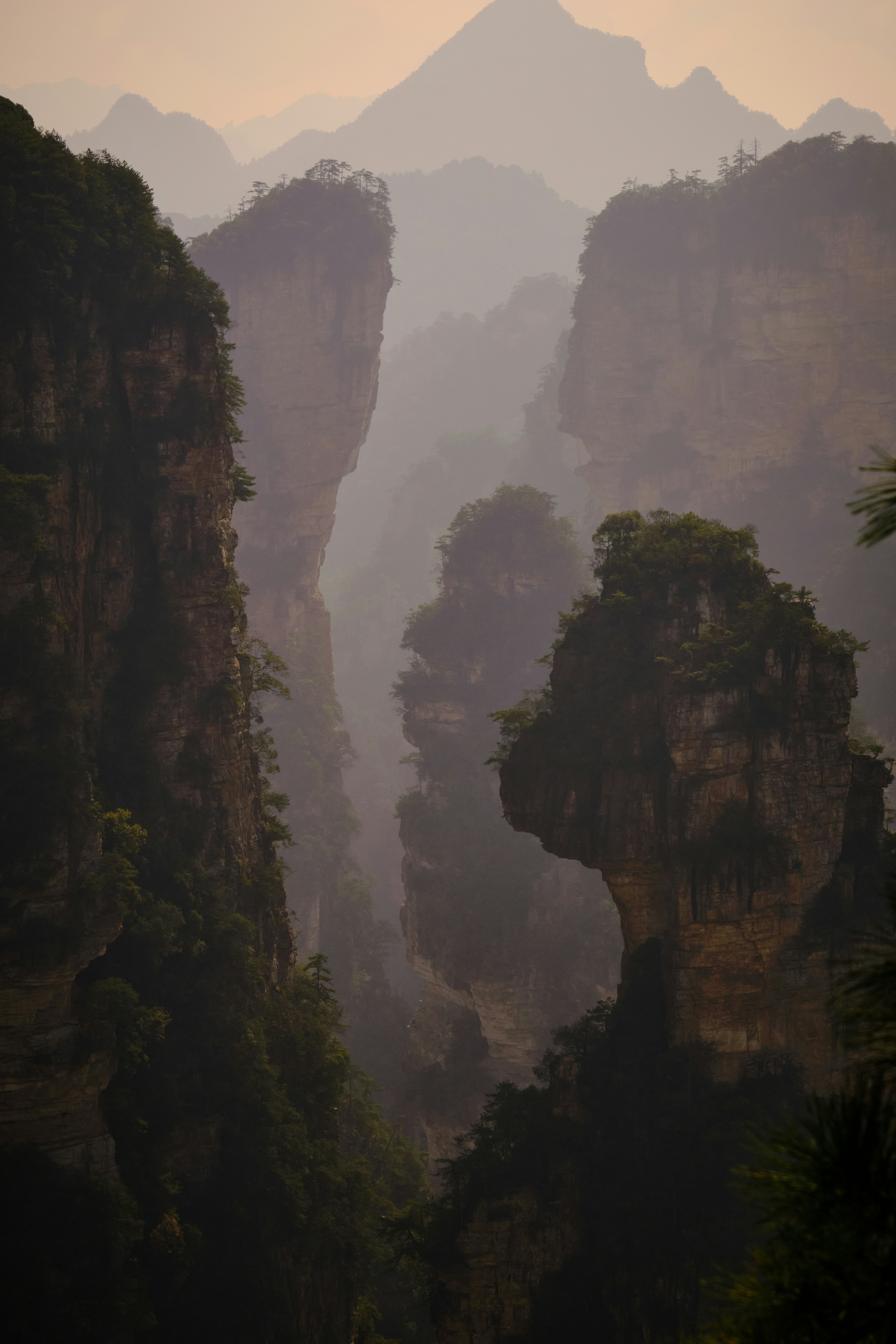 Misty landscape featuring towering rock formations shrouded in fog, creating an ethereal atmosphere. The scene captures the grandeur of nature's rugged beauty.