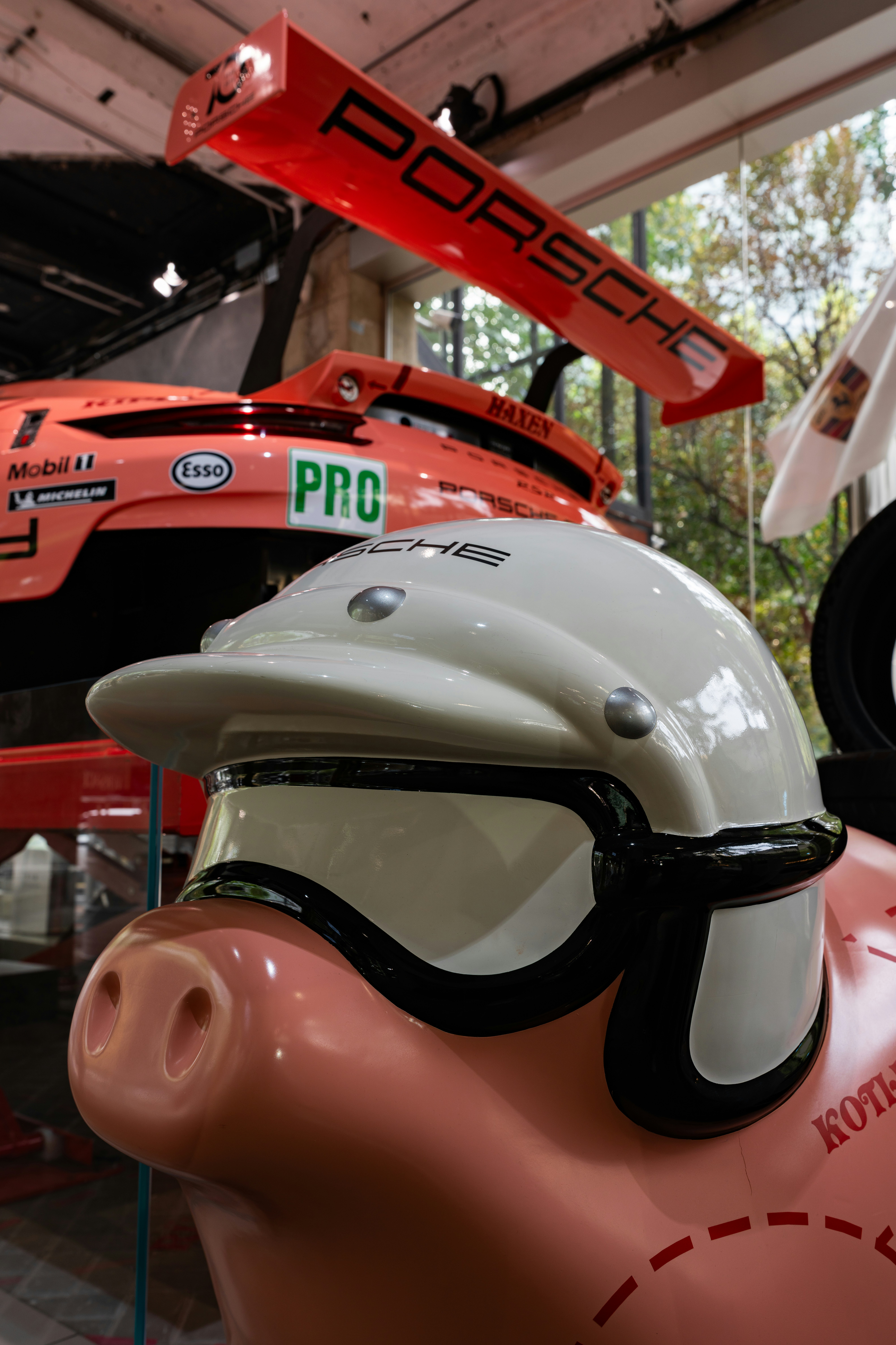 The Pit-Stop Porcine Guardian: Helmeted Pig Amid Porsche Racing Legacy