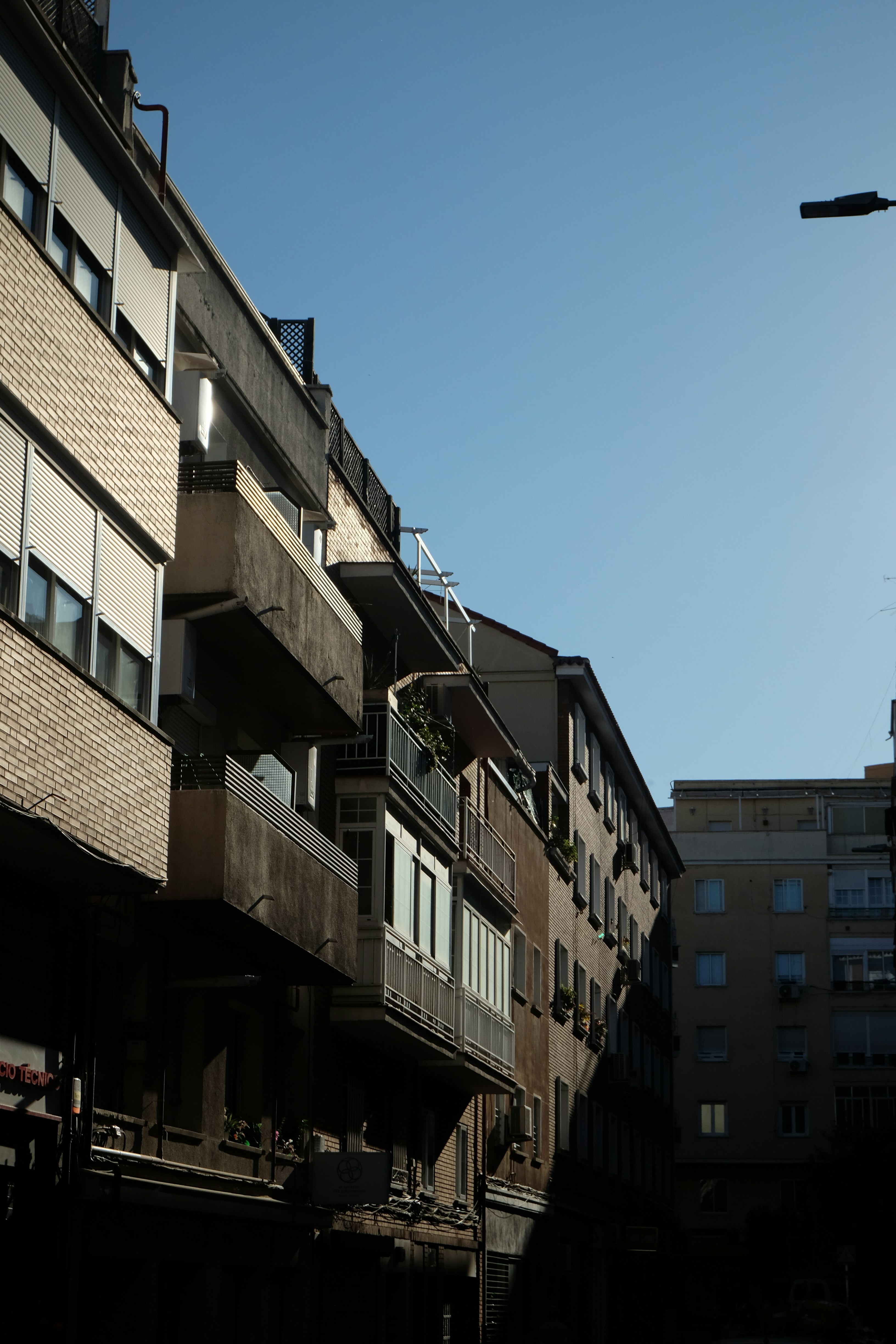 Silhouetted buildings create a striking contrast against a clear blue sky, emphasizing architectural lines and textures.