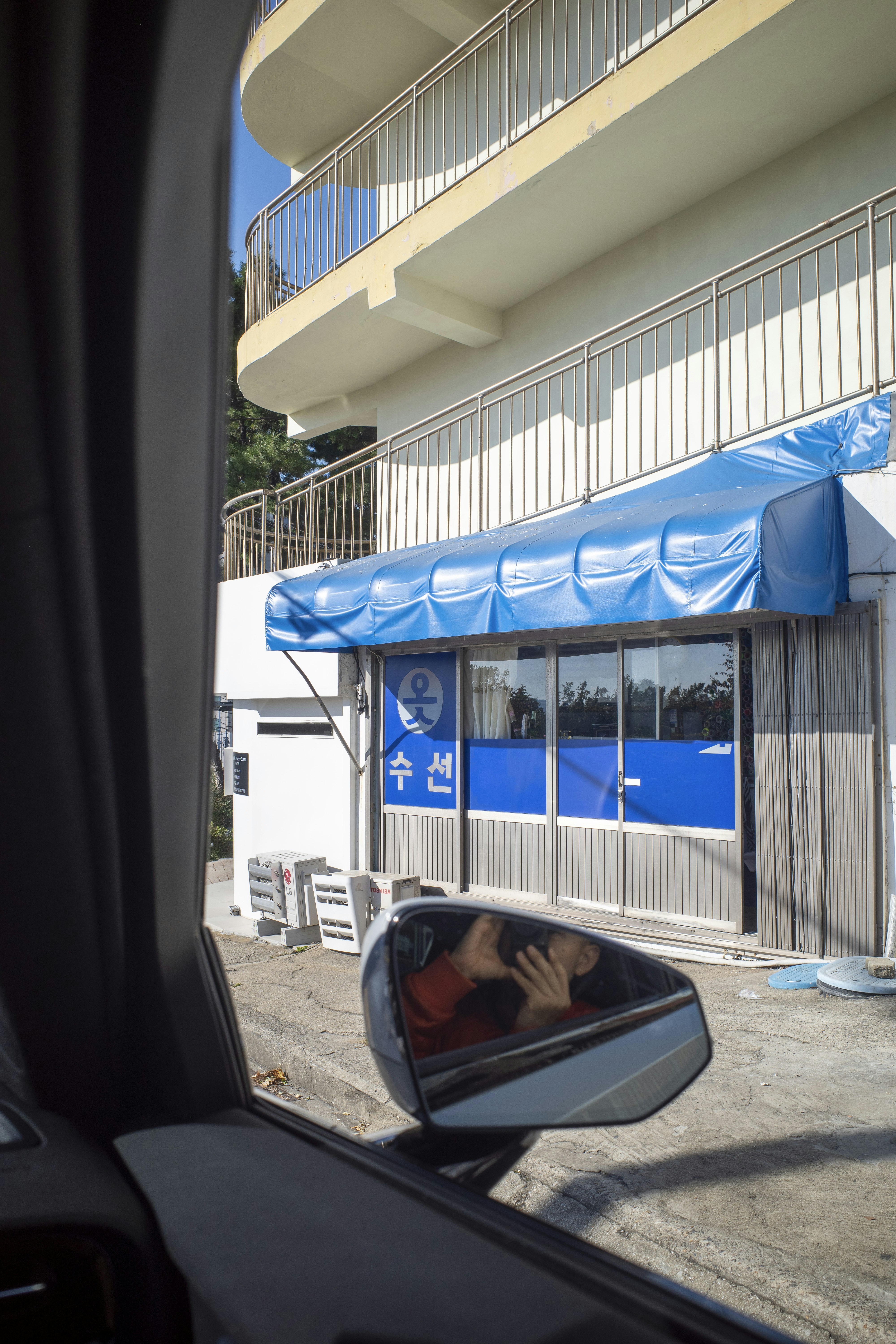 Blue Canopy and Street-Side Stop: A Glimpse from a Car Window
