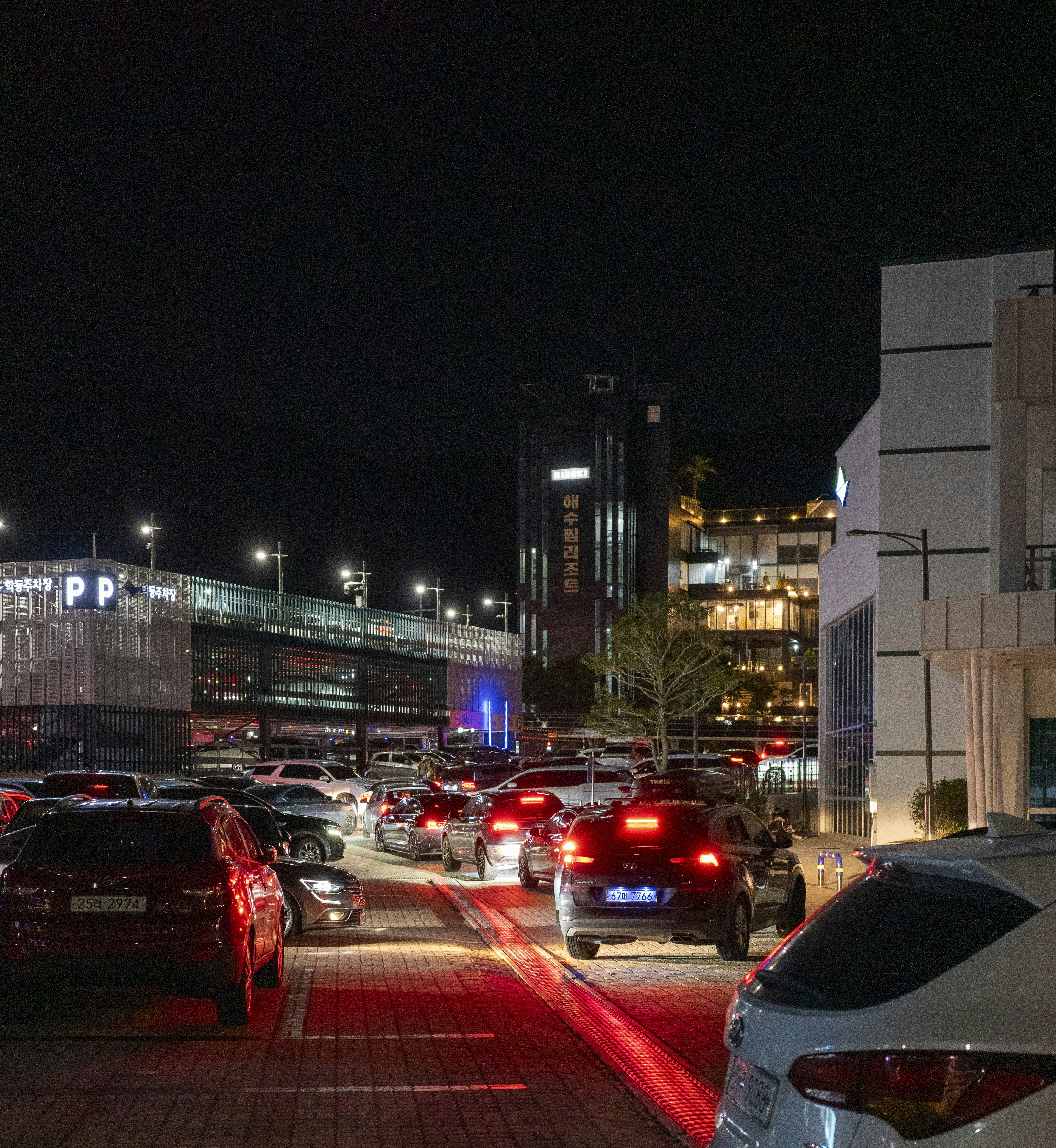 Red Taillight Corridor: Nighttime Traffic Lines a Modern Campus Parking