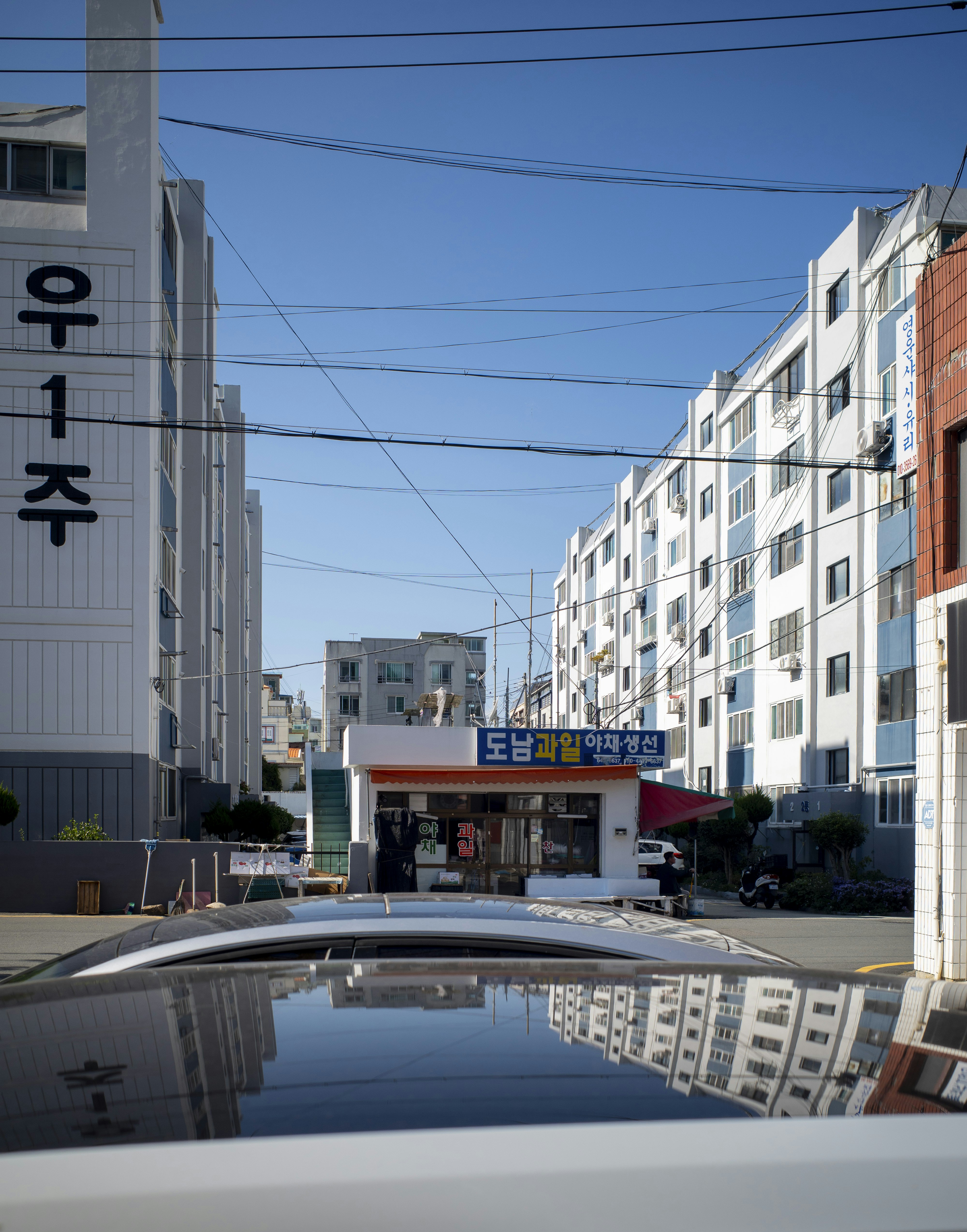 Blue Sign Corner: A Quiet Korean Street Framed by Towers and Reflections