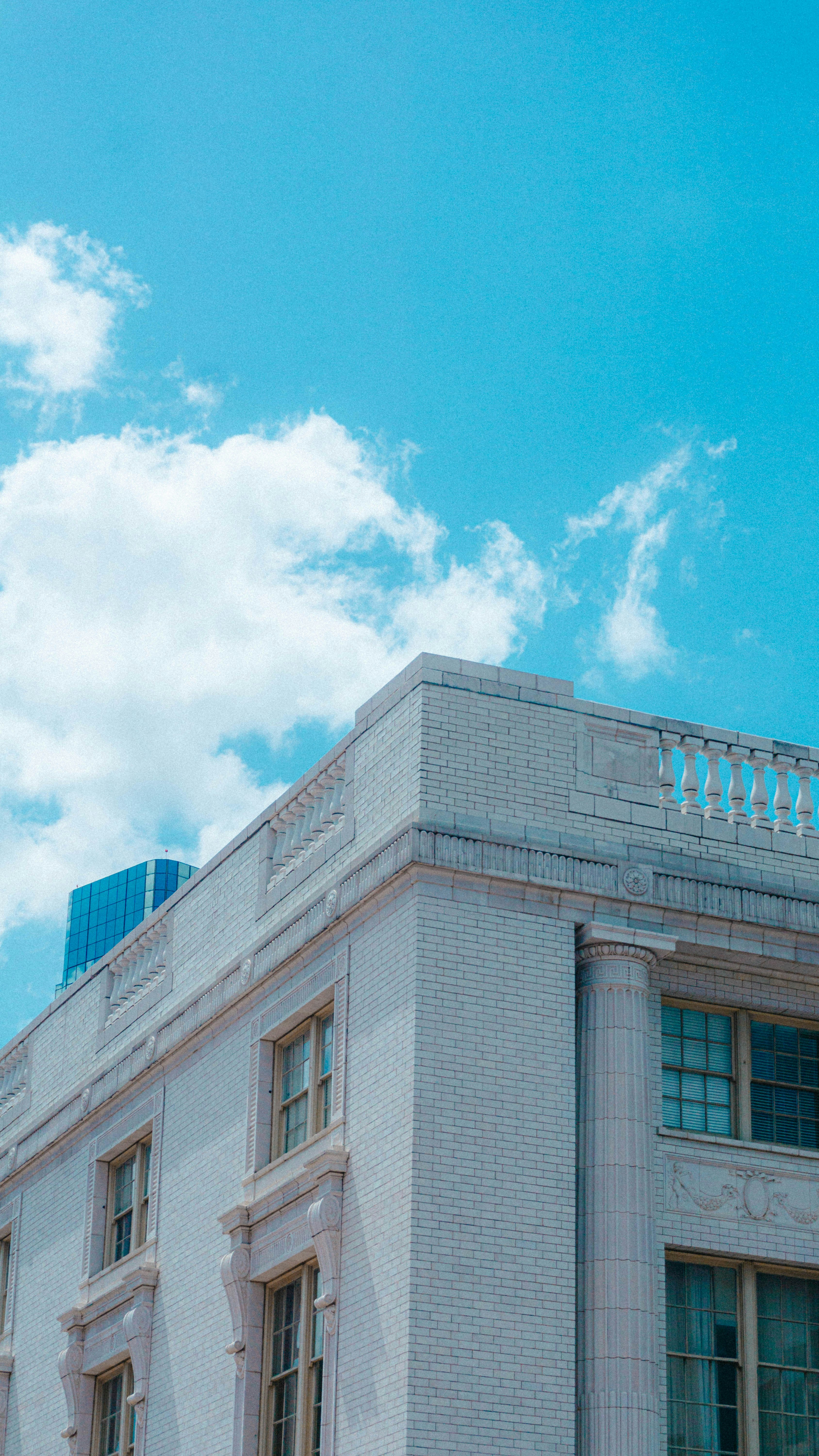 Historic building corner showcasing intricate architectural details under a bright blue sky with fluffy clouds.