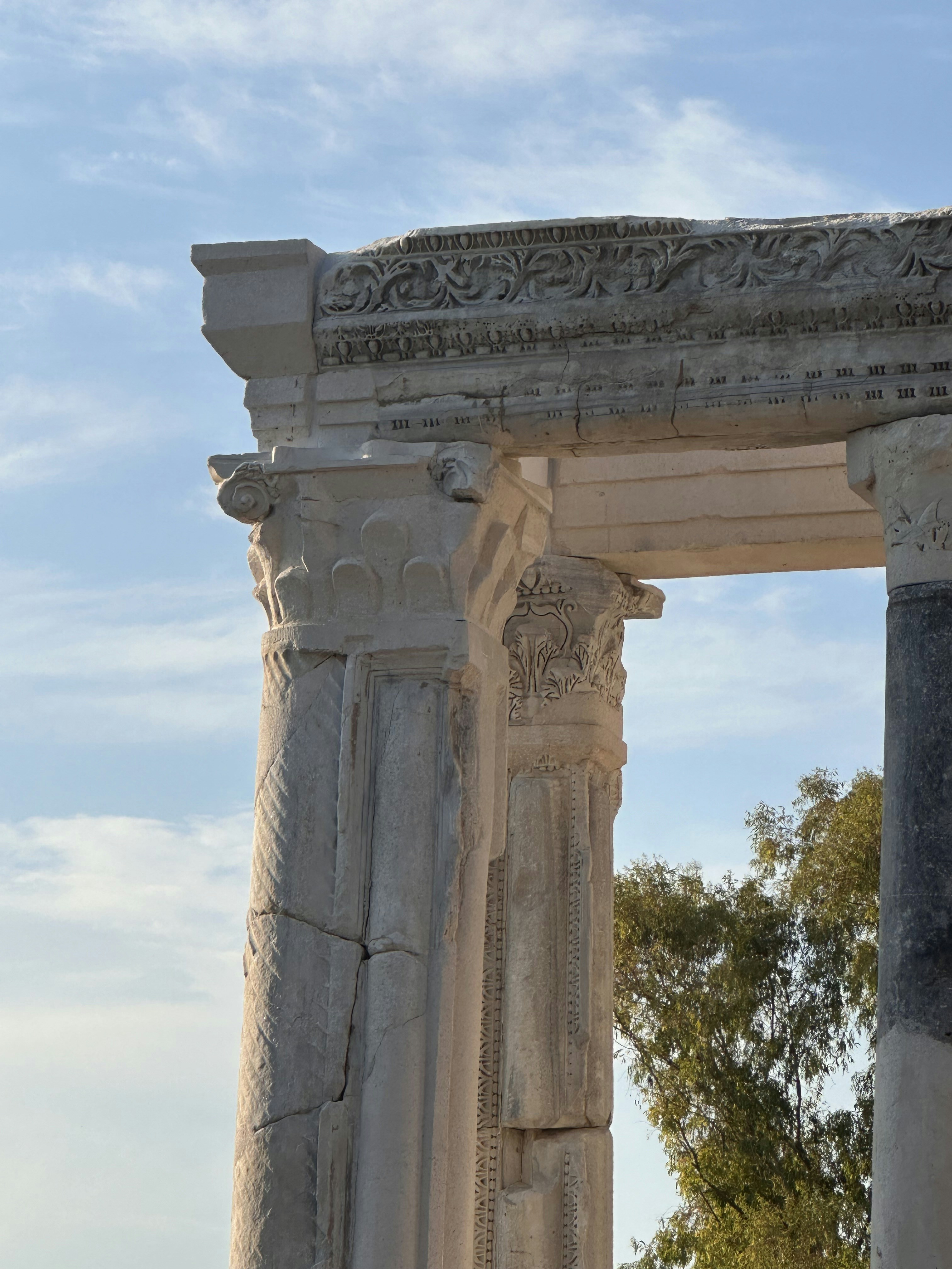 Intricately carved stone columns supporting a classical archway against a clear sky.