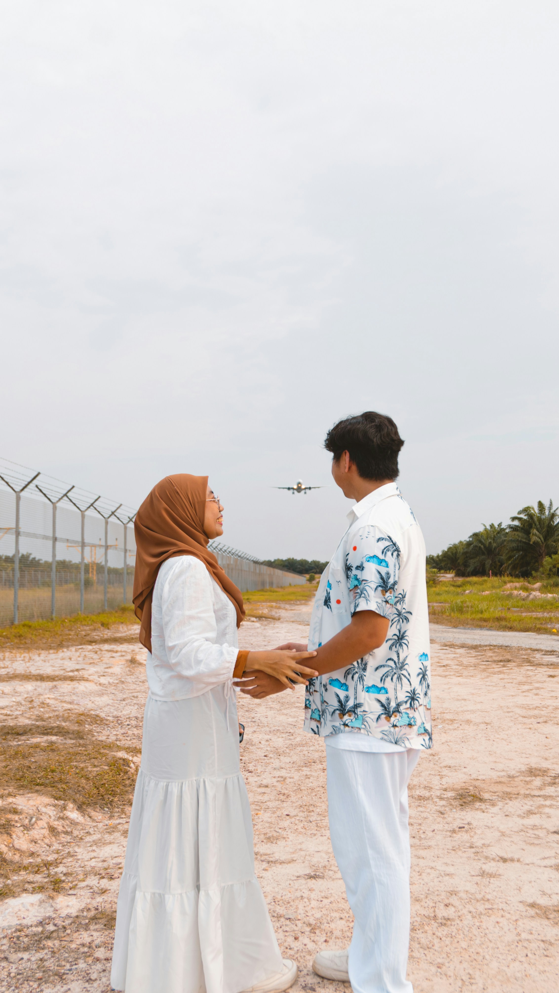 Handshake at Horizon: A Quiet Moment on a Dusty Airstrip as a Plane Passes