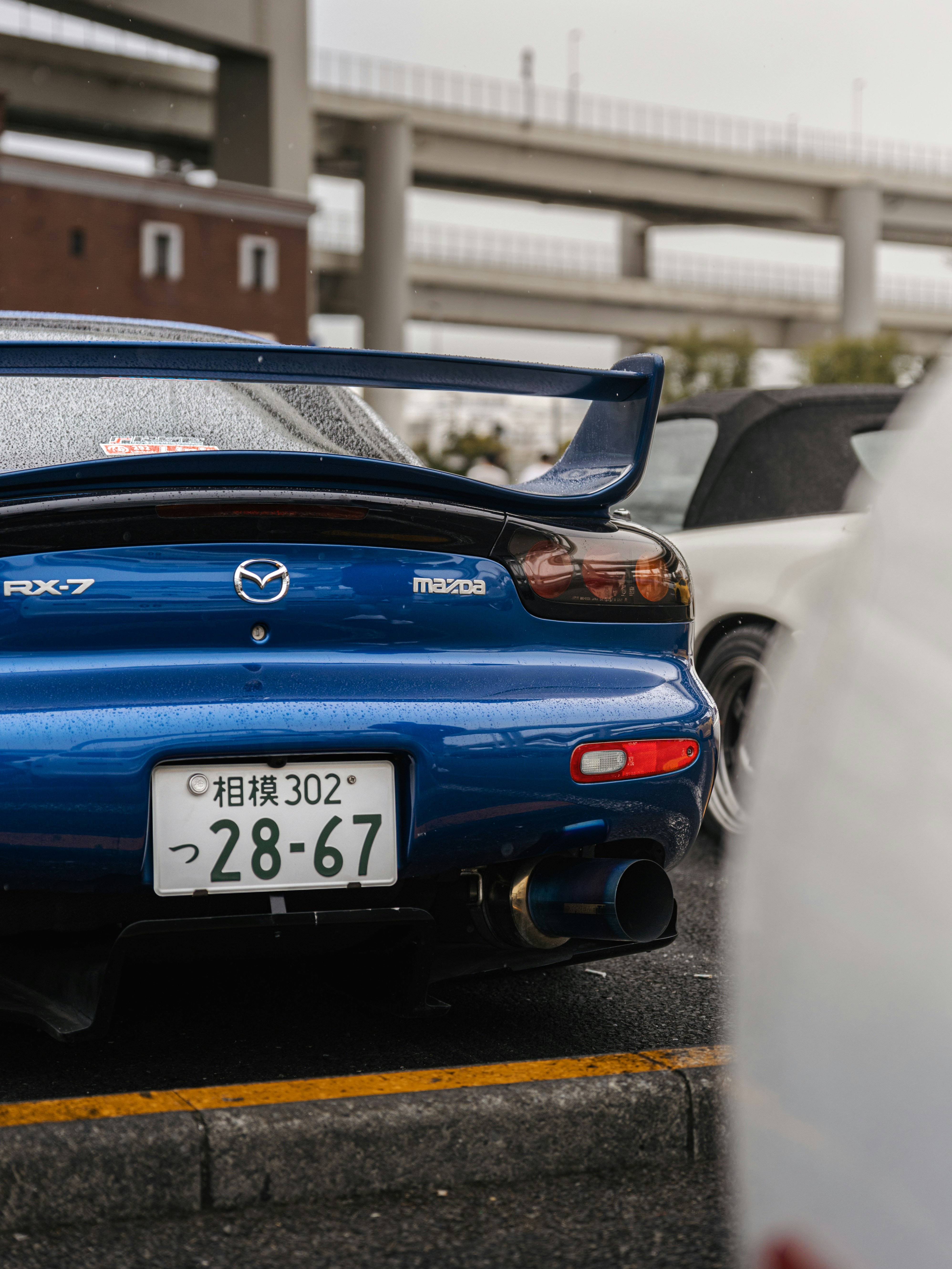 Blue Mazda RX-7 Rear: Spoilered Silhouette in a Parking Lot Backdrop