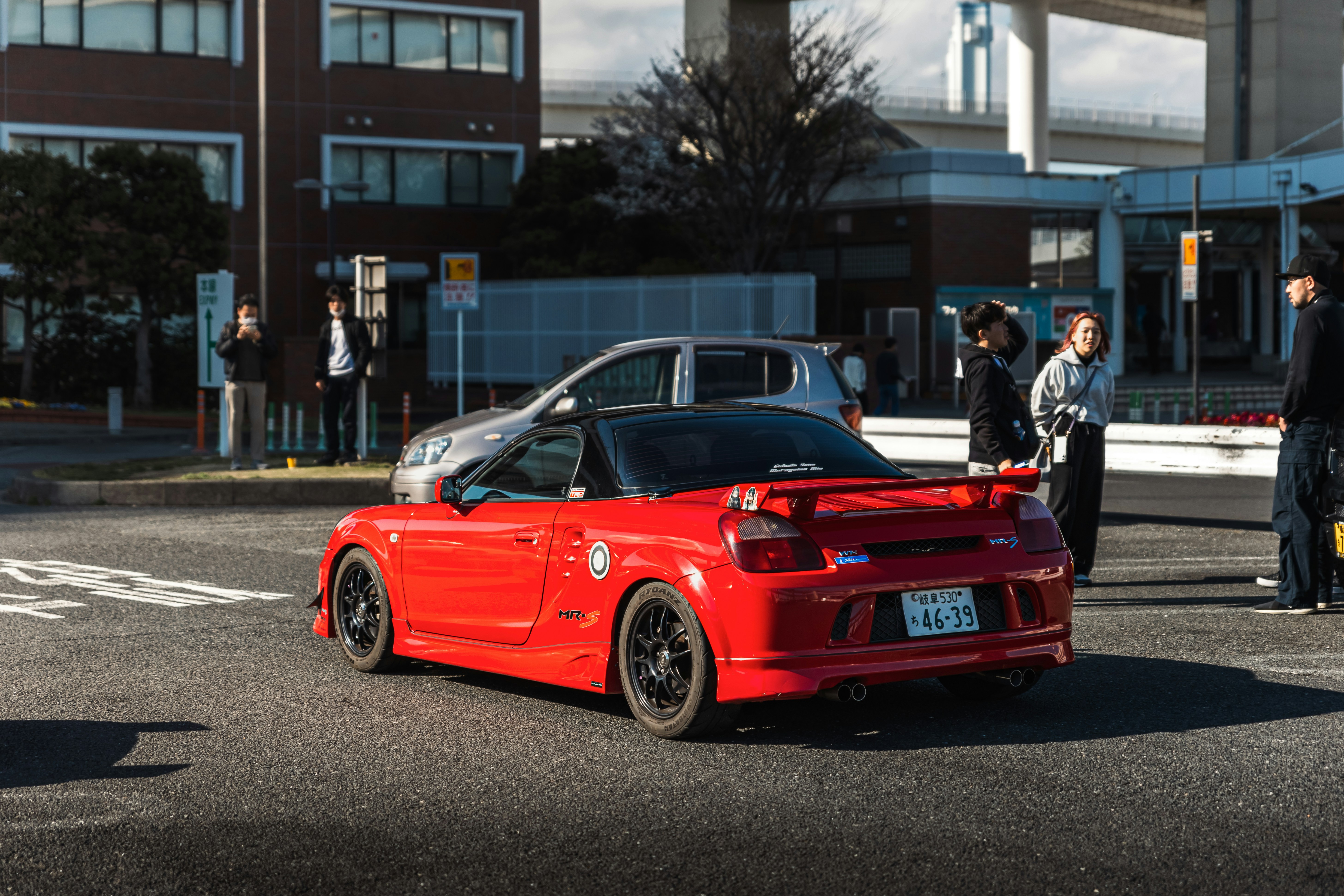 Red sports car parked on a street with people. photo – Free Sports car ...