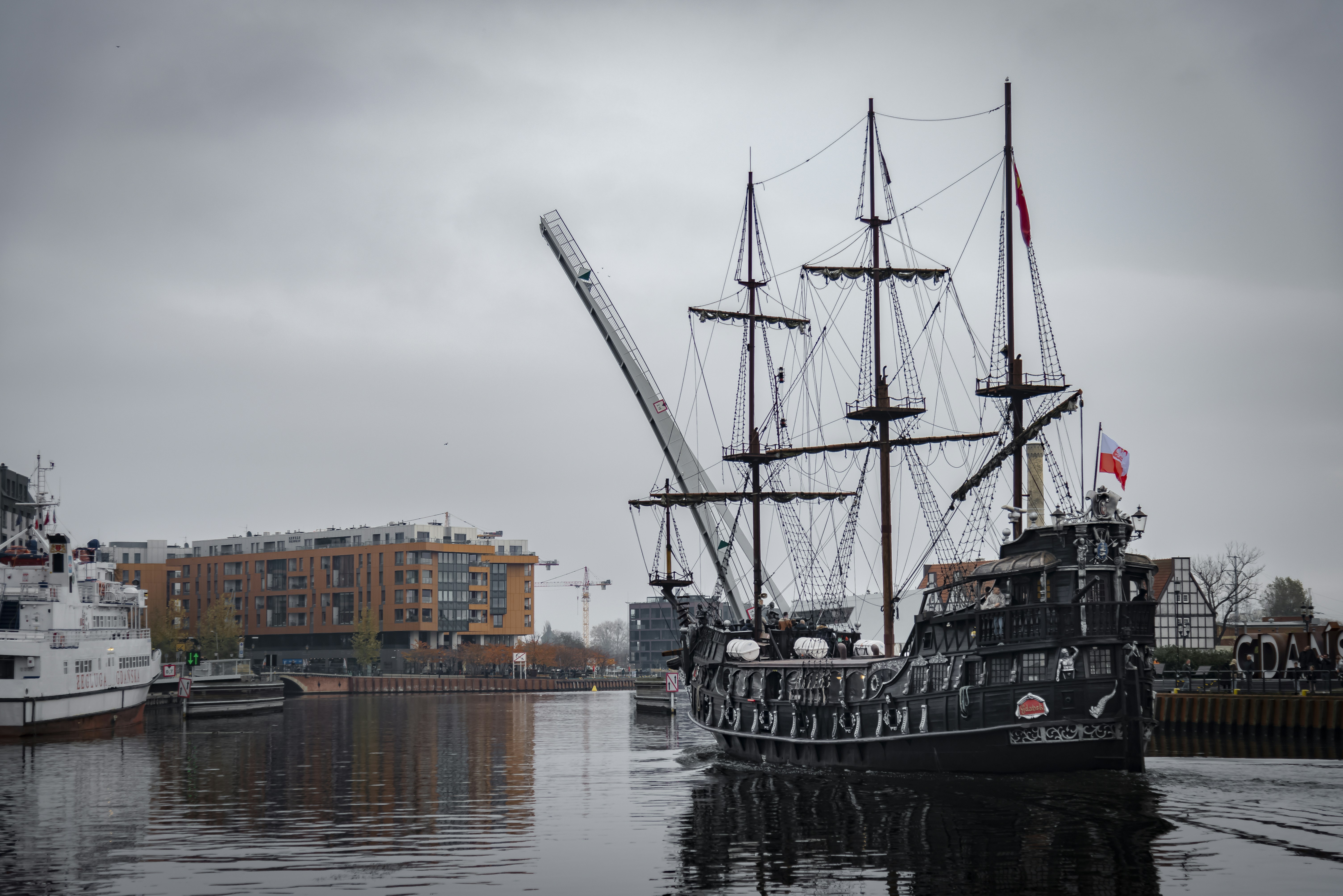Black-Hulled Schooner Anchored Amid Modern Harborscape