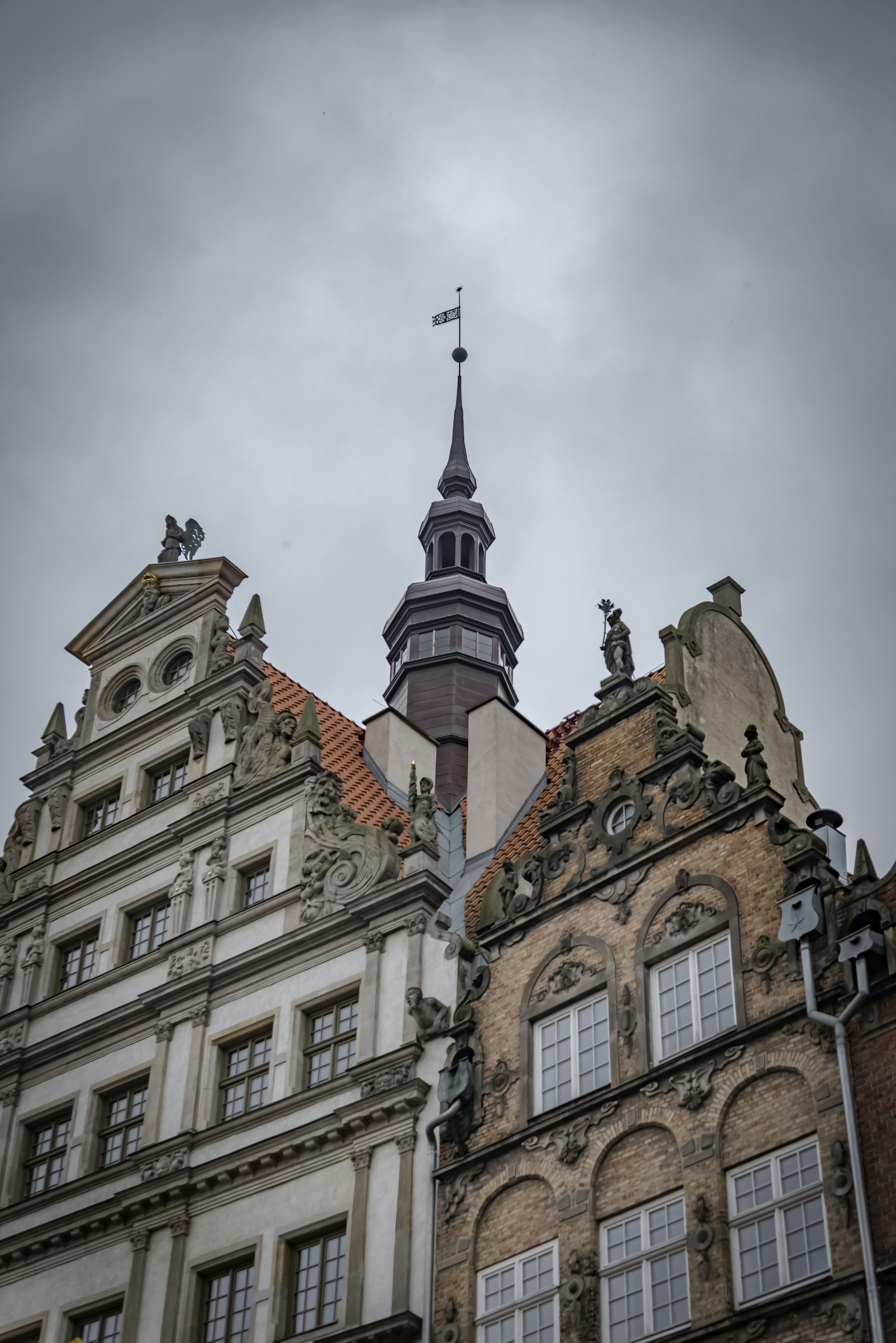 Spire Crowned by Cloudy Sky Above Ornate City Facades