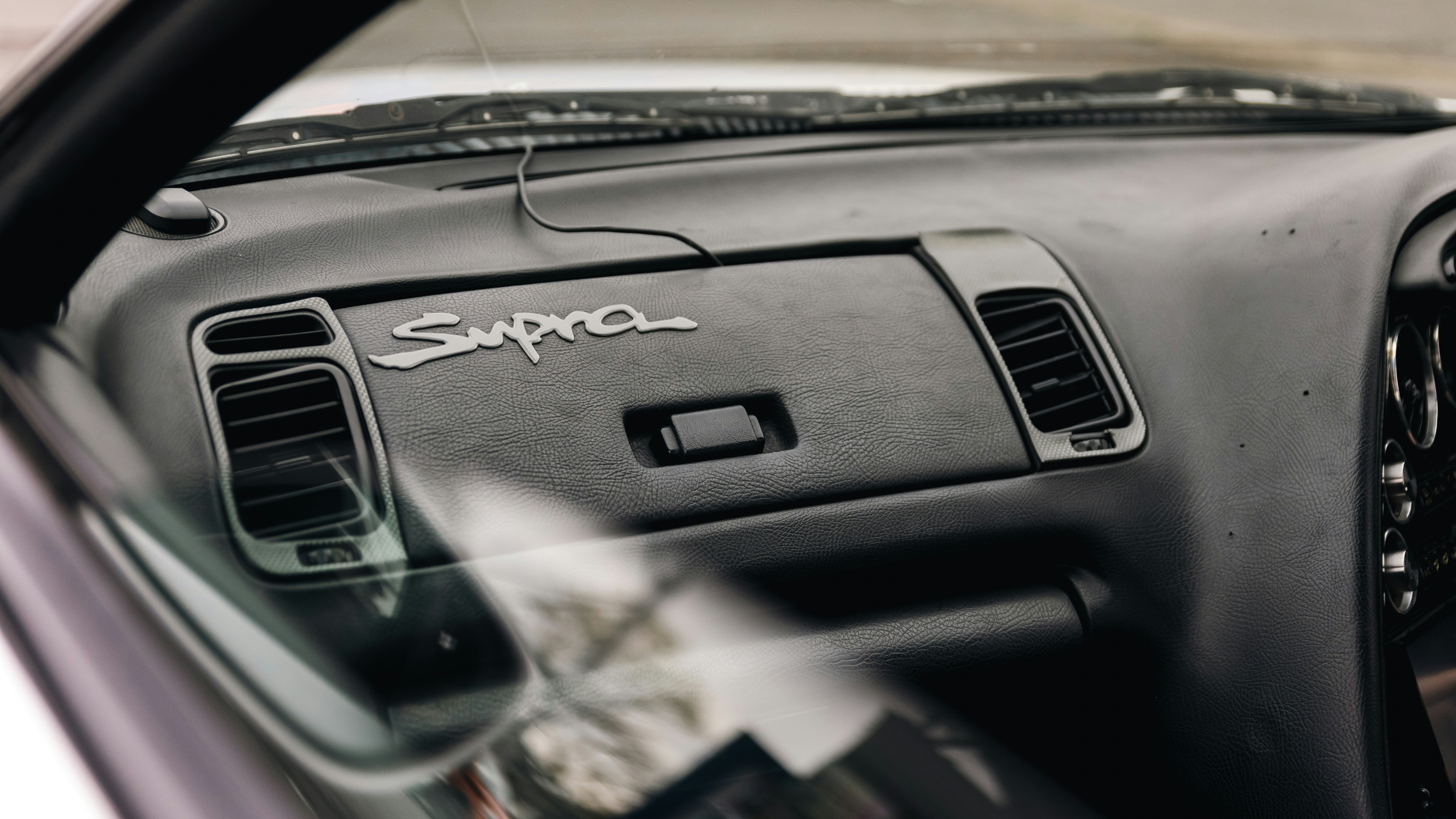 Monochrome Dashboard: The Supra Emblem Anchoring a Quiet Interior