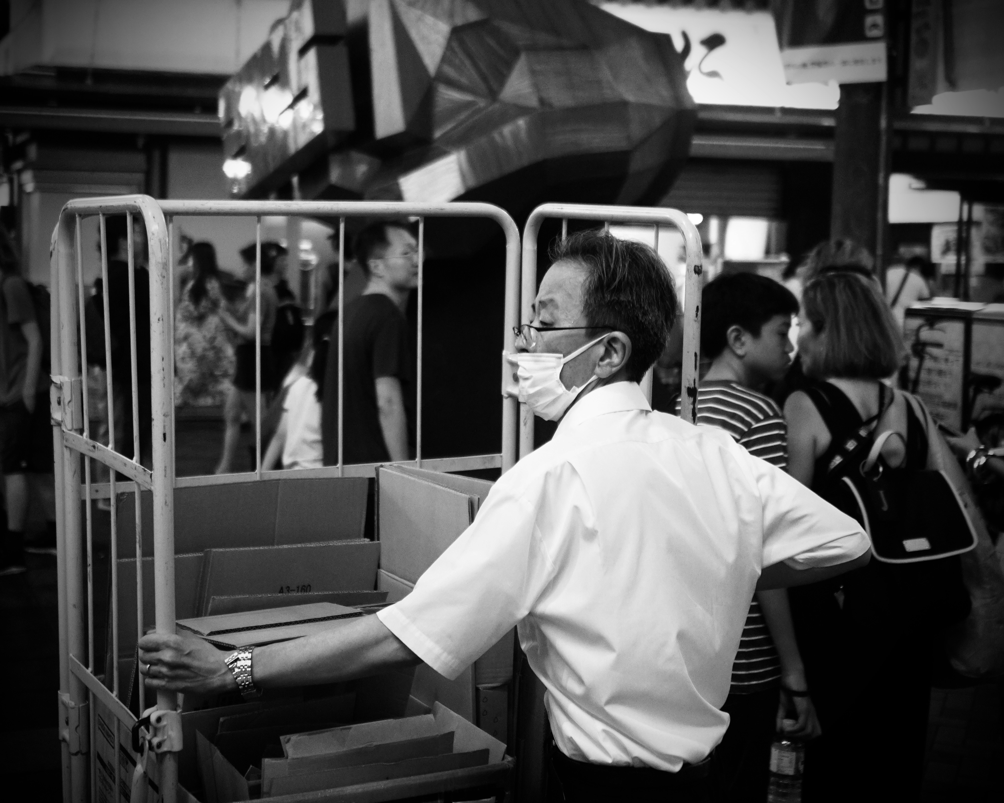 Man wearing mask pushes cart in busy market