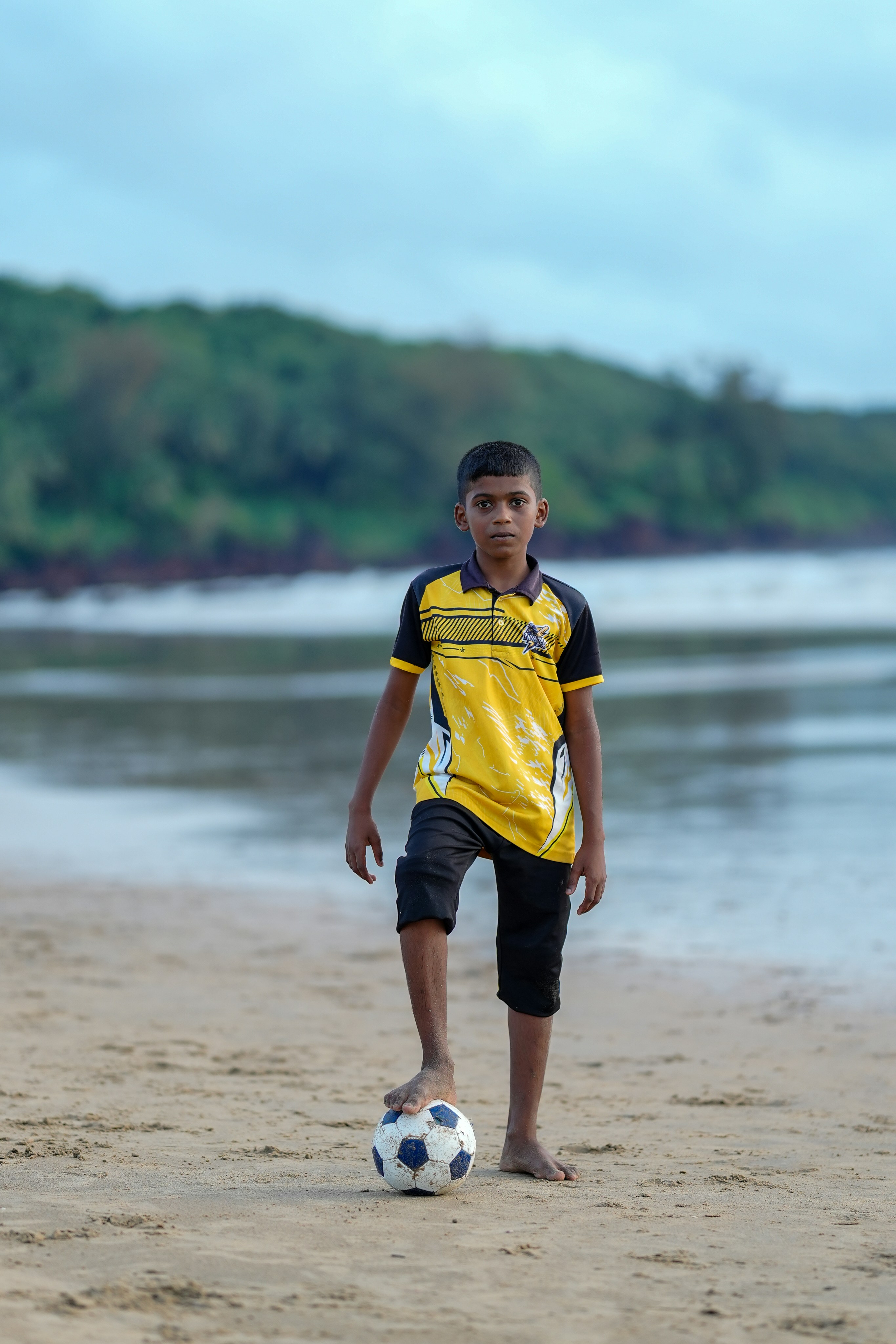 Shoreline Dribble: A poised young player anchors a soccer ball at the tide's edge