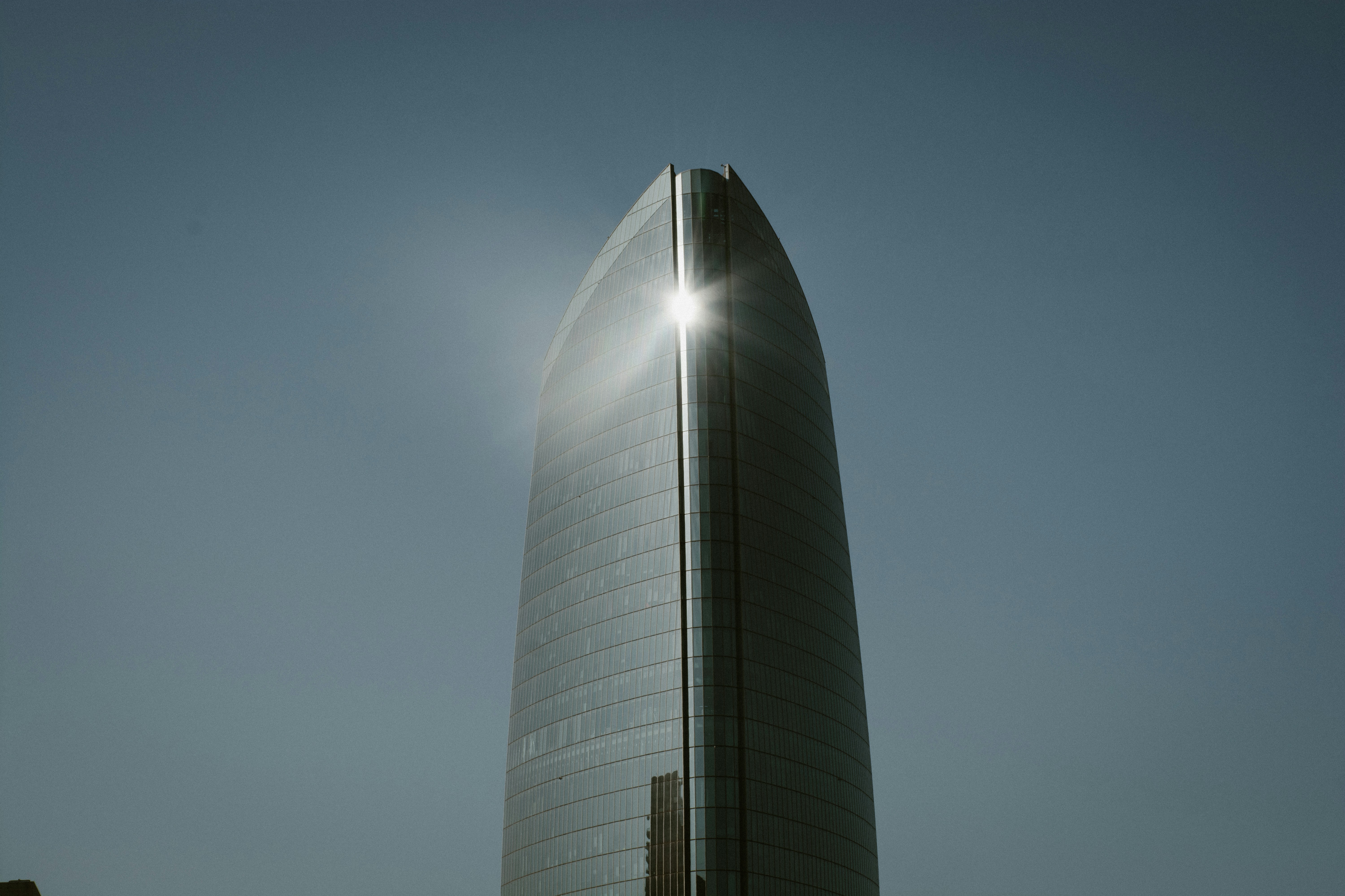 Sunflare on the Glass Spine: A Skyward Tower Against Blue
