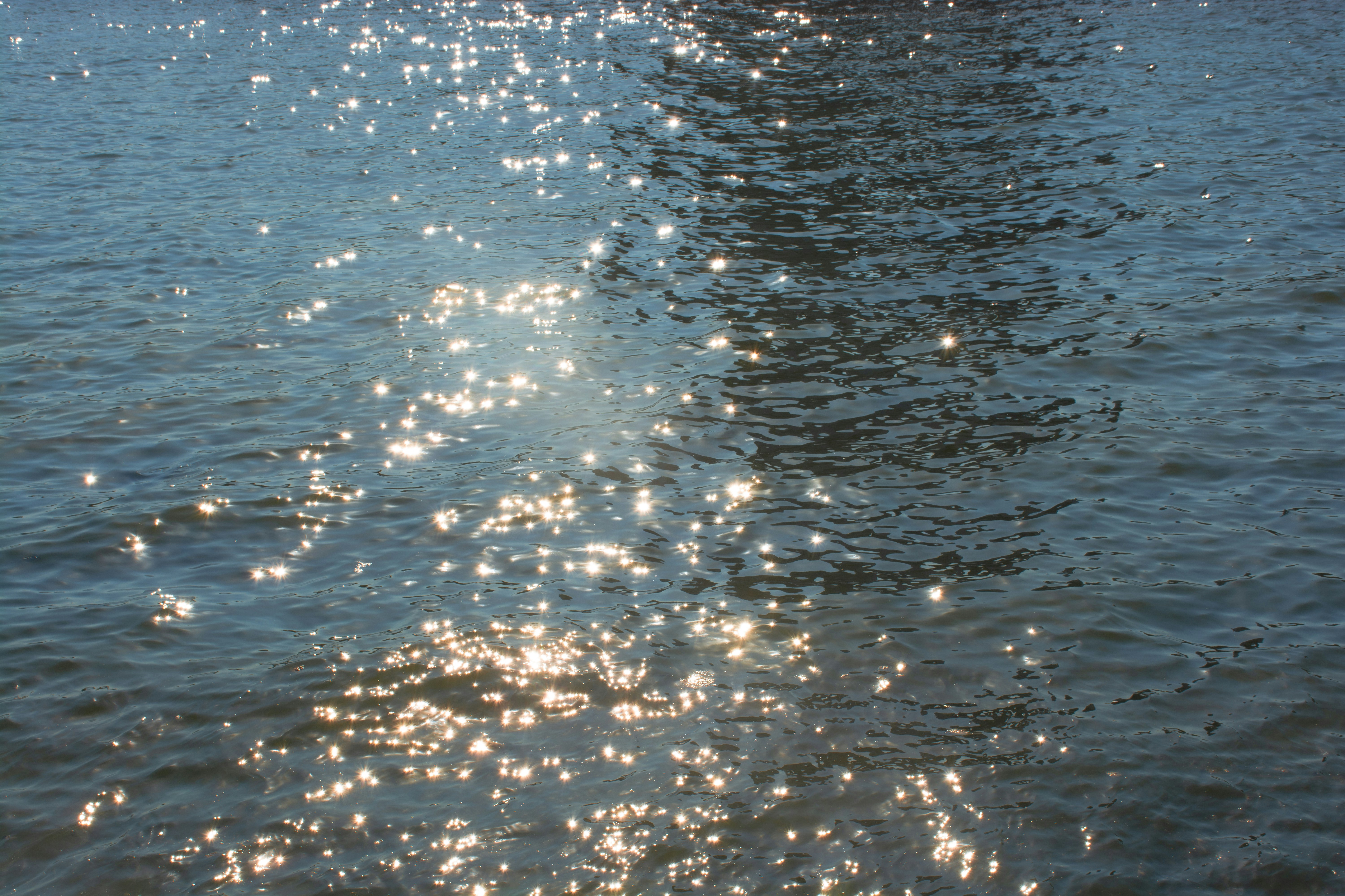 La luz del sol brilla en la superficie del agua ondulante. foto ...