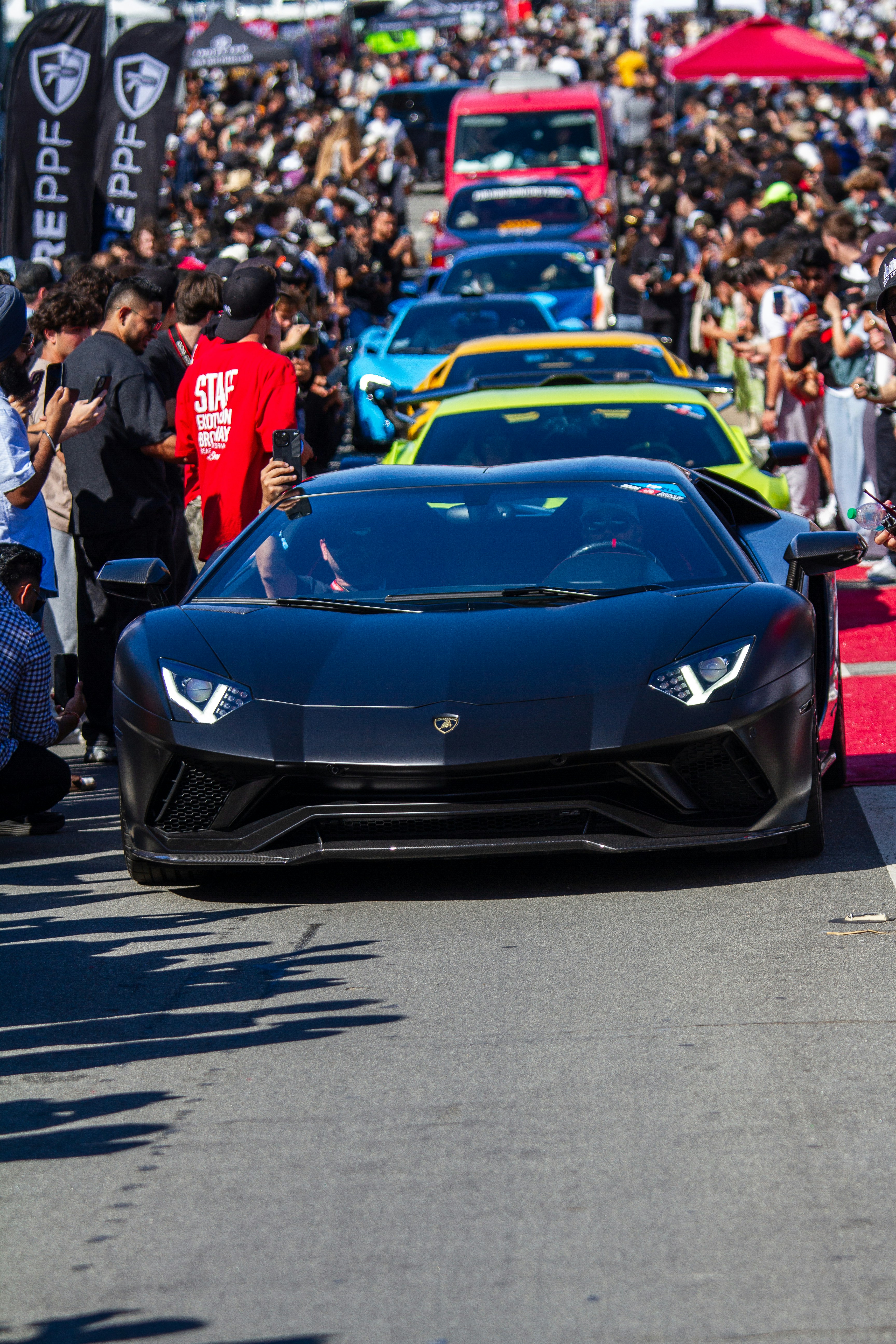 Front-Row Thunder: A Matte Black Lamborghini Leads a Parade of Neon Supercars