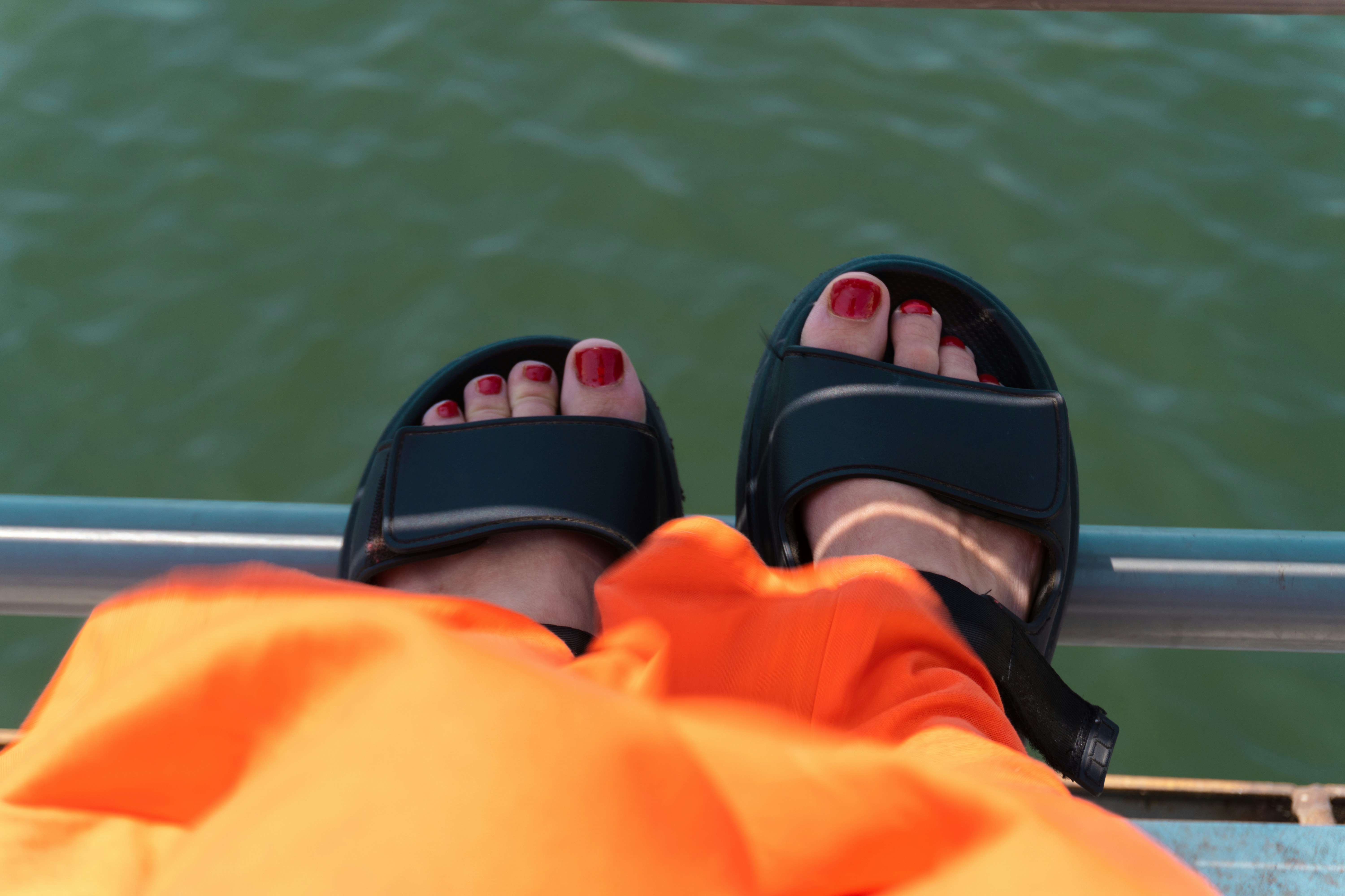 Dockside Footing: Orange Drapery Framing a Quiet Green Sea