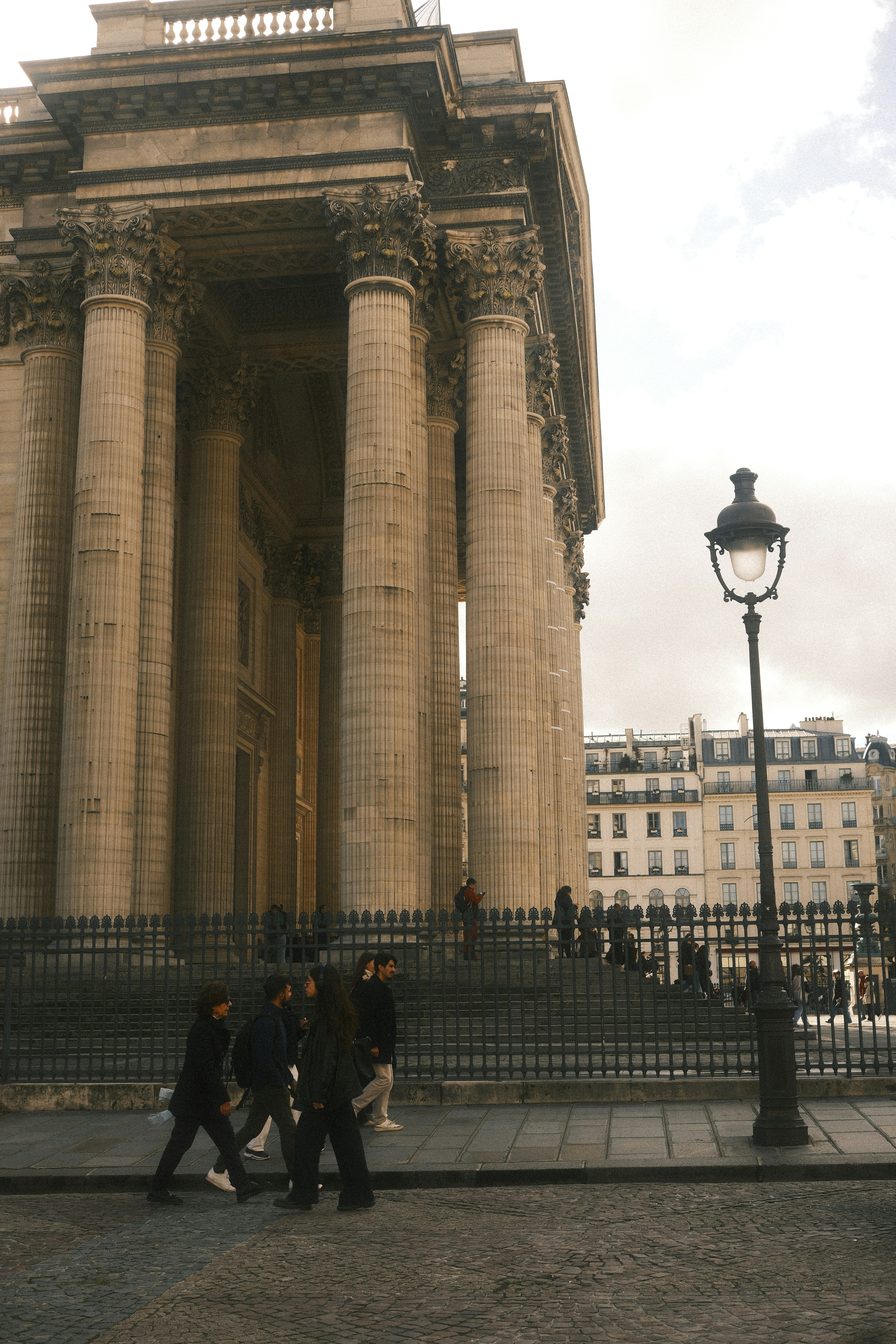 Stone Colonnade at Dusk: Pedestrians Along a Grand Facade