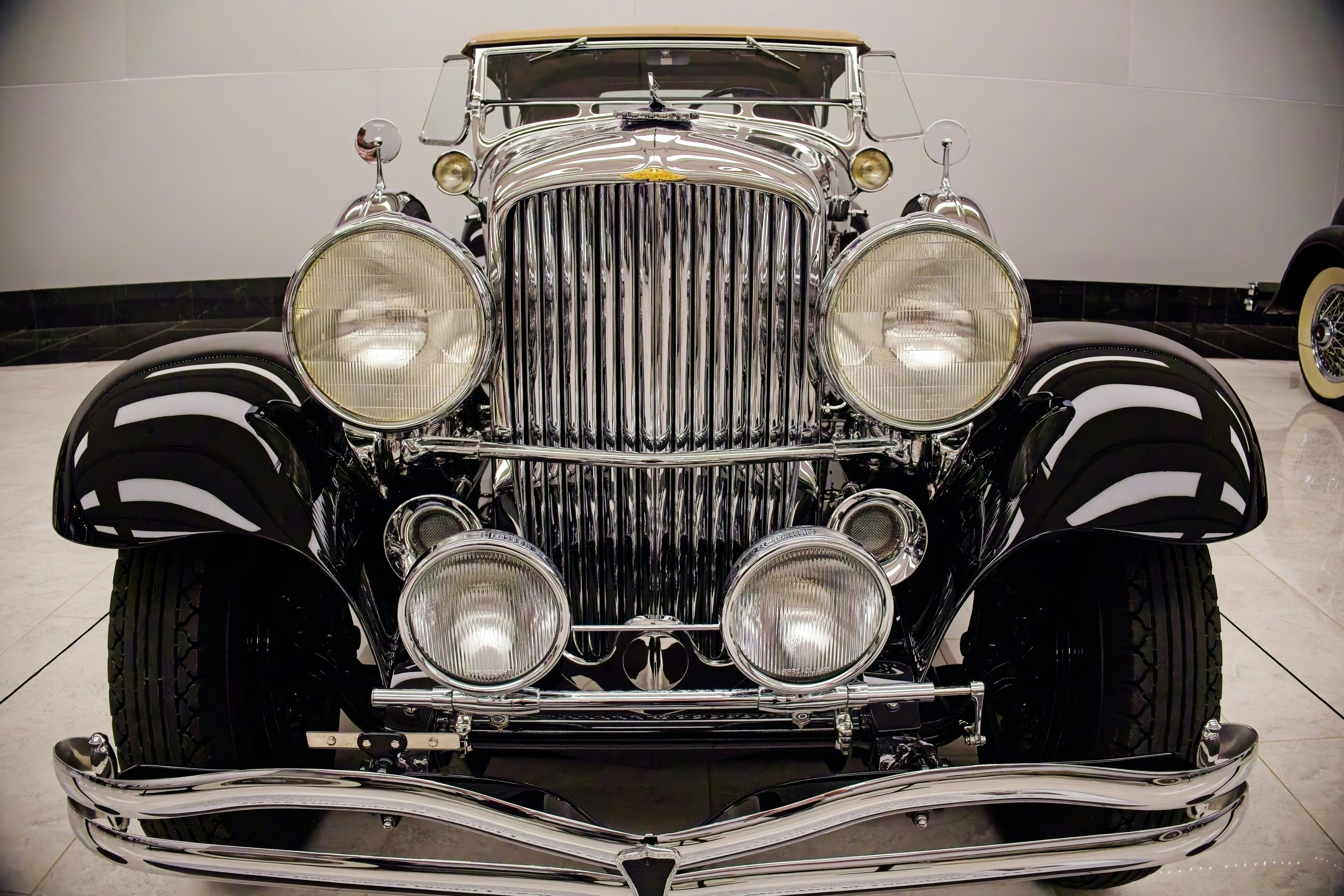 A Duesenberg luxury car from the 1920s. | A shiny black vintage convertible car