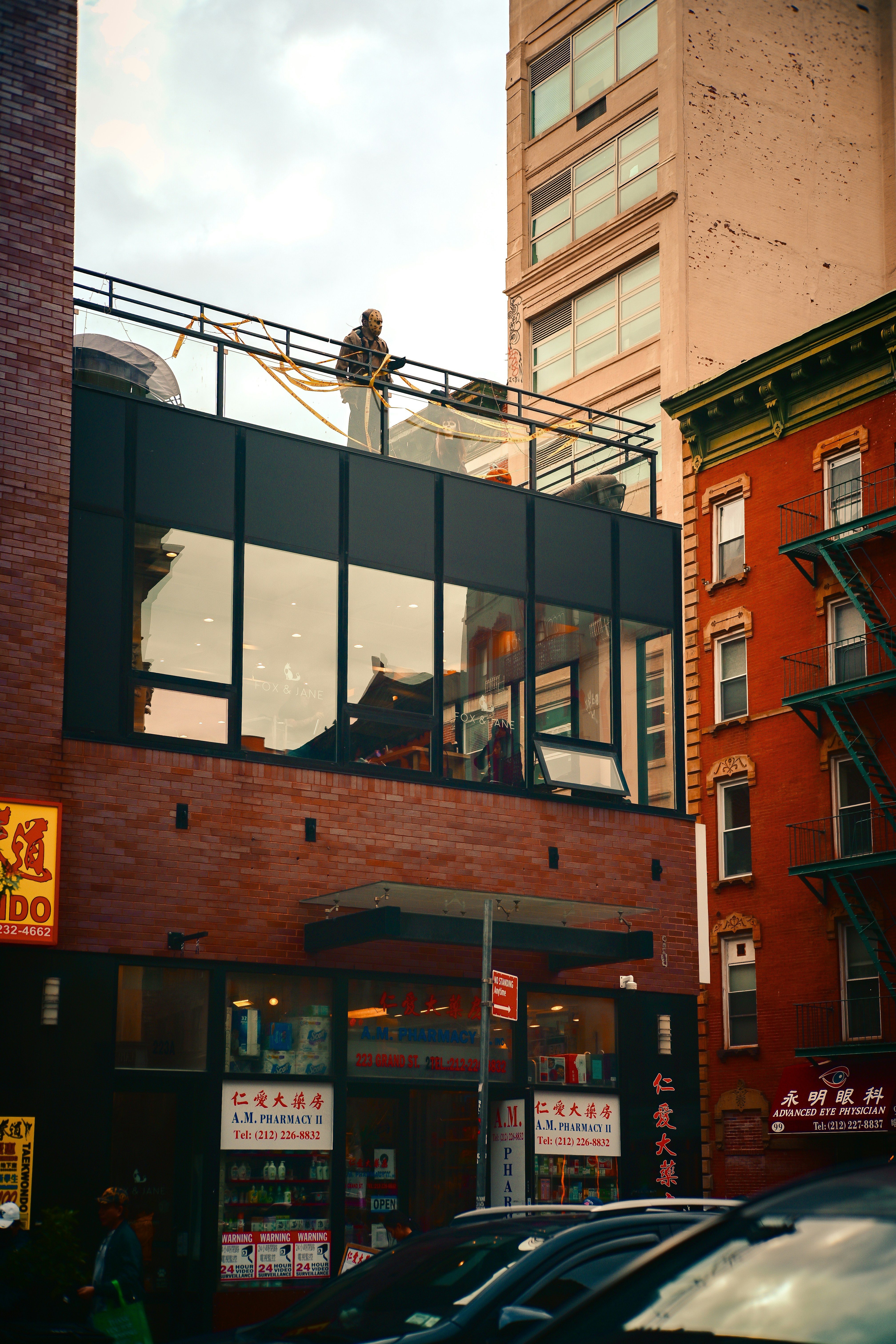Lofty Gaze Over Glass: A Rooftop Figure Over a City Facade