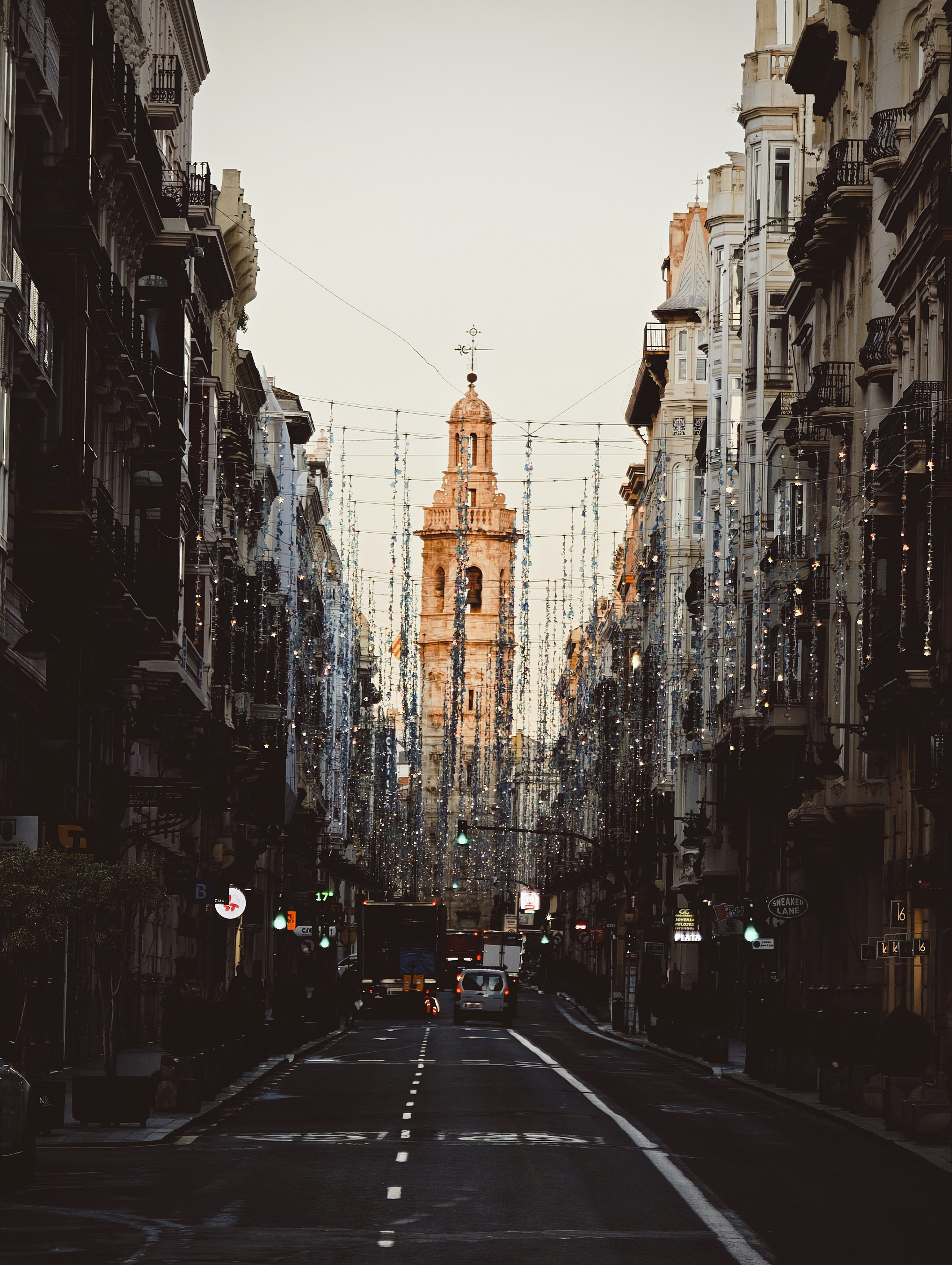 Street with ornate buildings and tower at dusk.