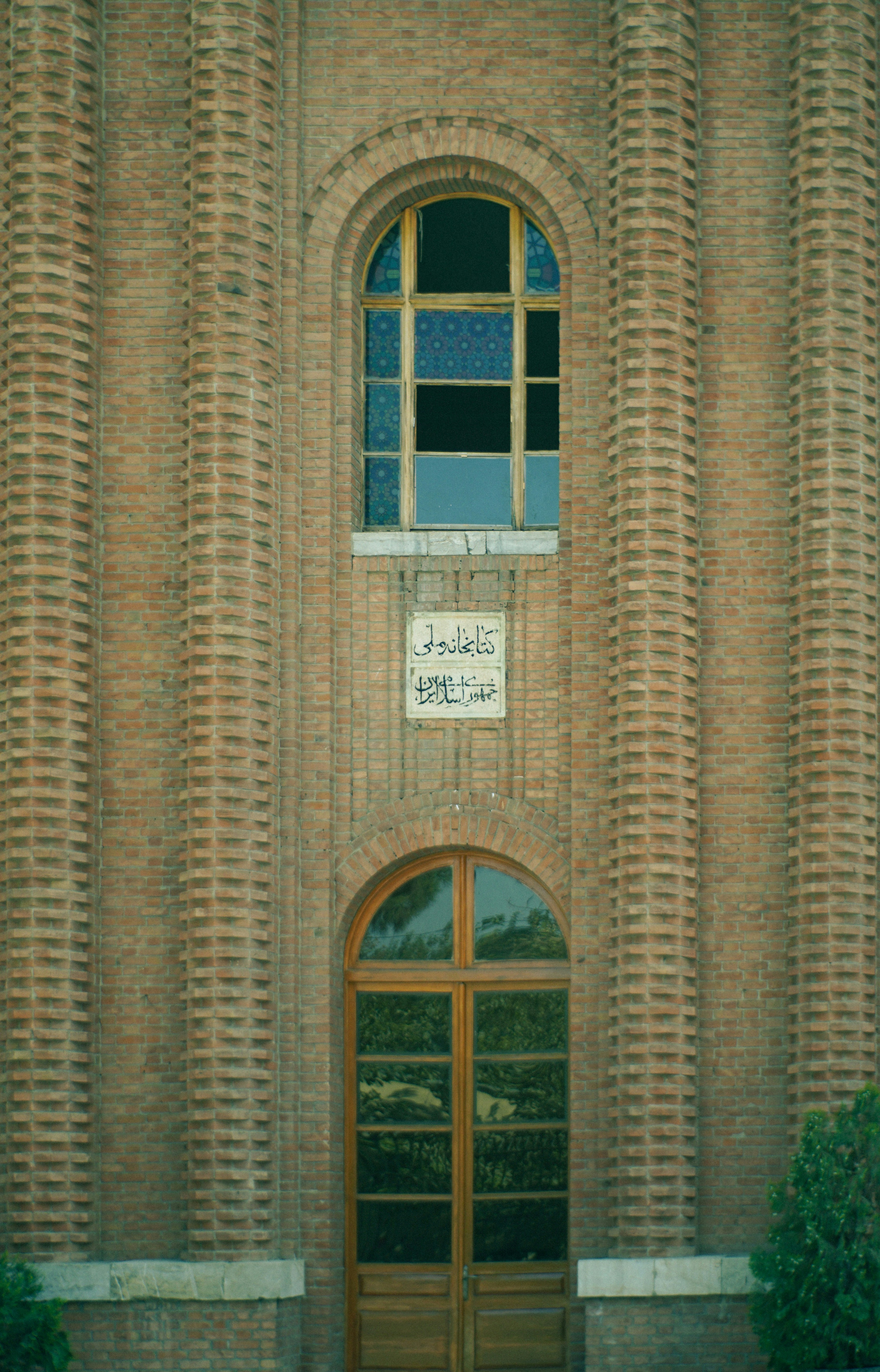 An entrance to worlds of imagination. | Arched wooden door and window on brick building