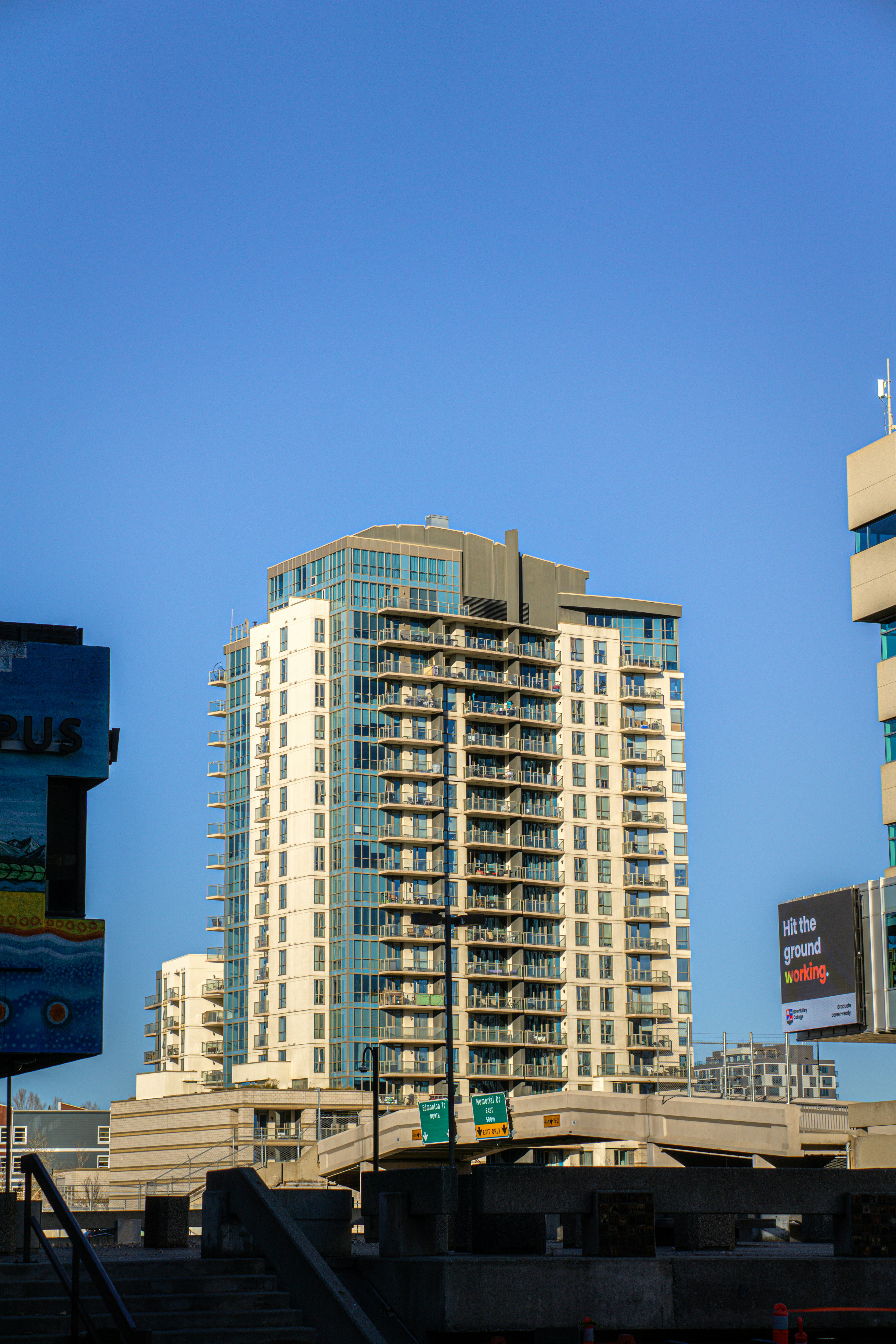 Contemporary high-rise building with reflective glass and balconies under a clear blue sky.