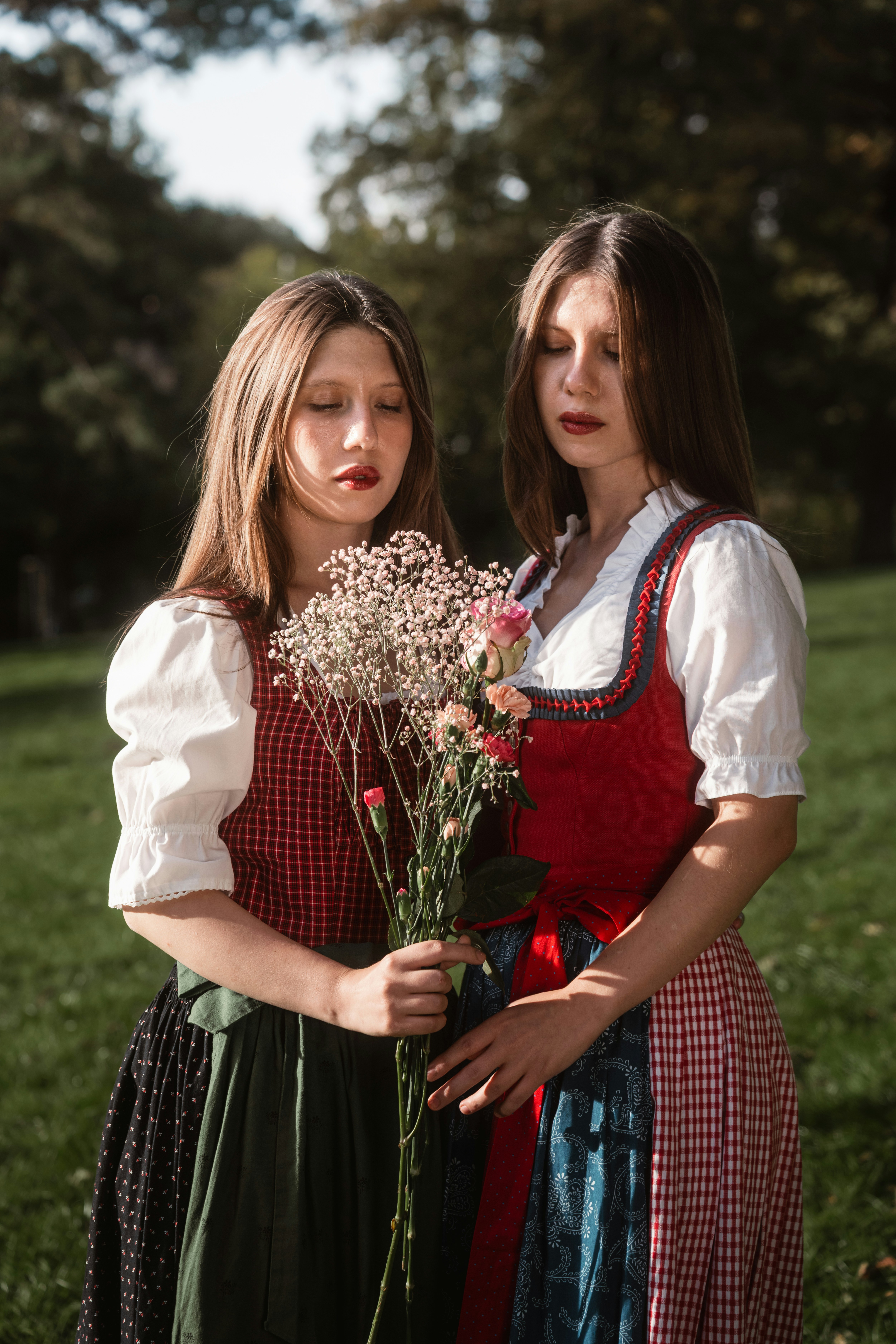 Floral Sisters in Bavarian Dresses | Two young women in traditional german dresses holding flowers