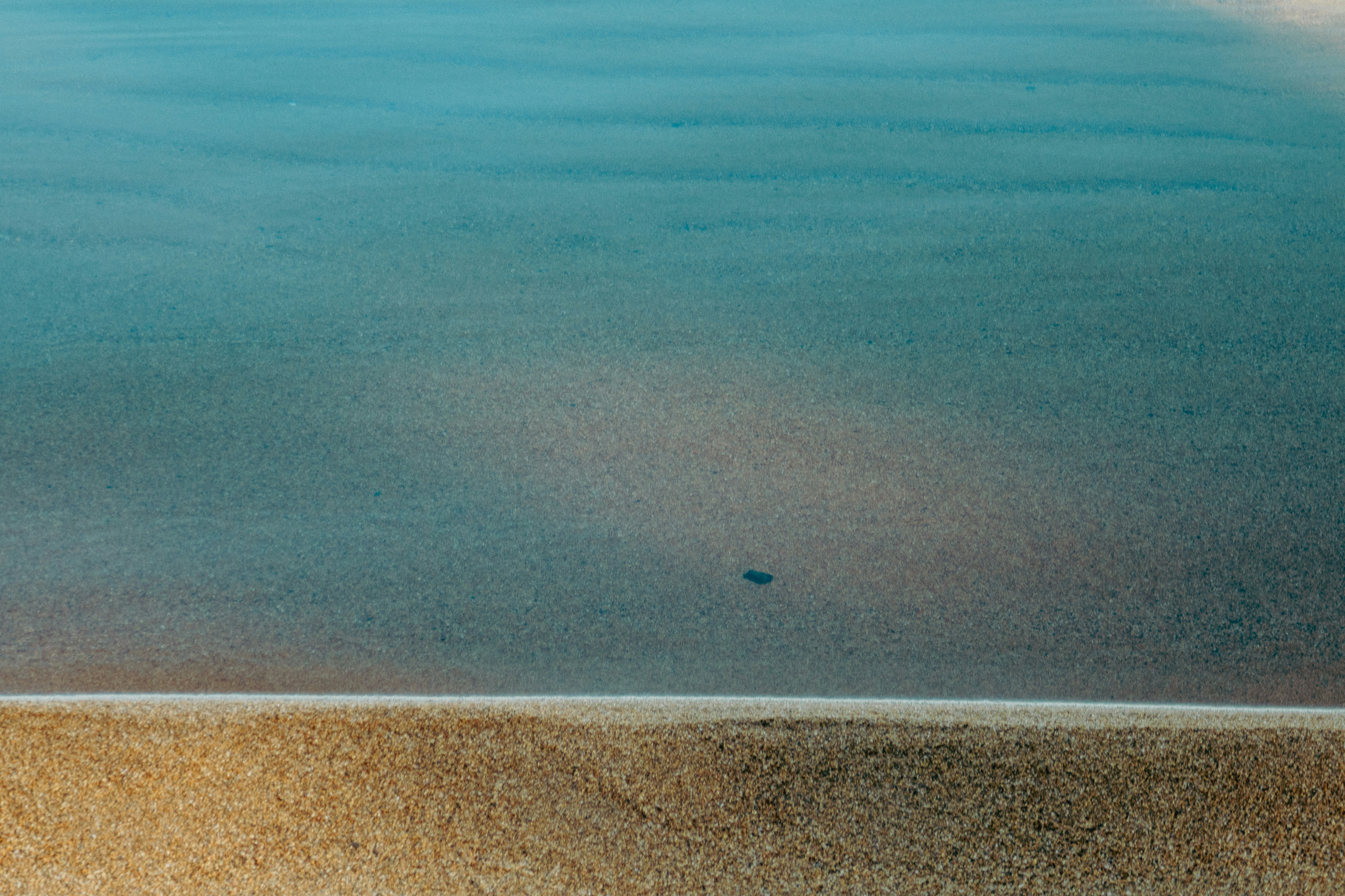 A small boat floats on a calm blue sea.