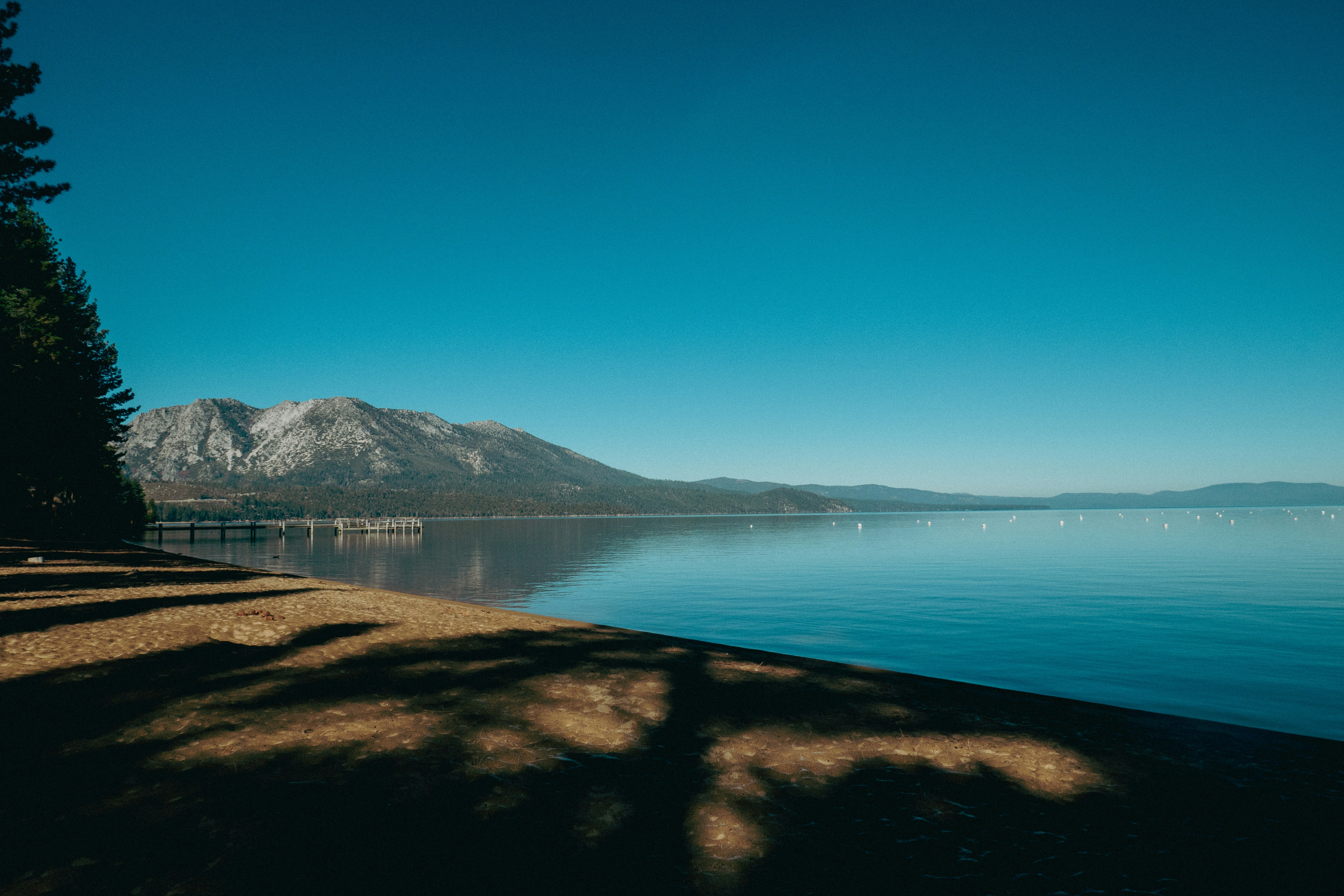 Calm lake with mountains under a clear blue sky.