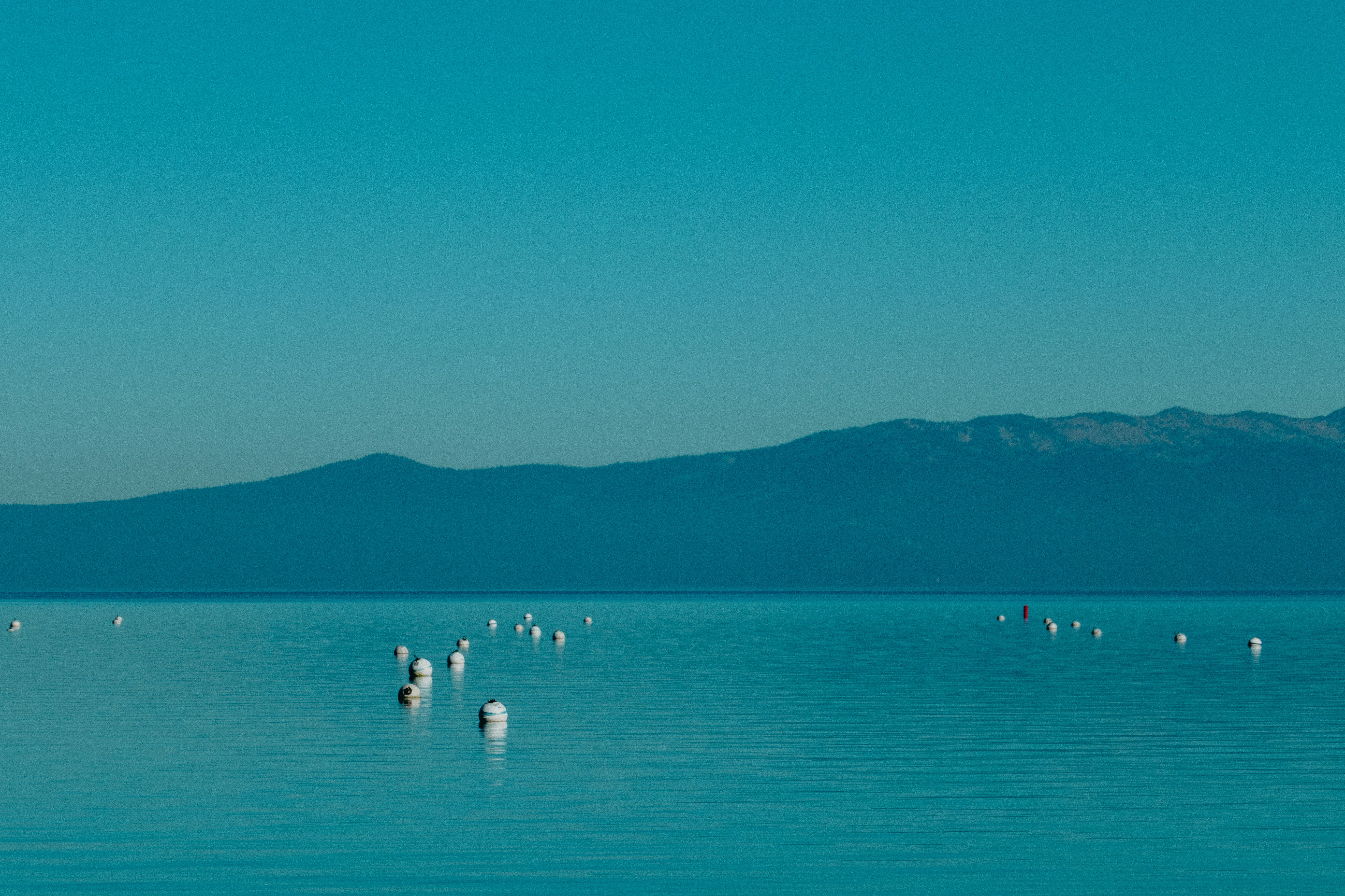 White objects floating in calm turquoise water with mountain background ...