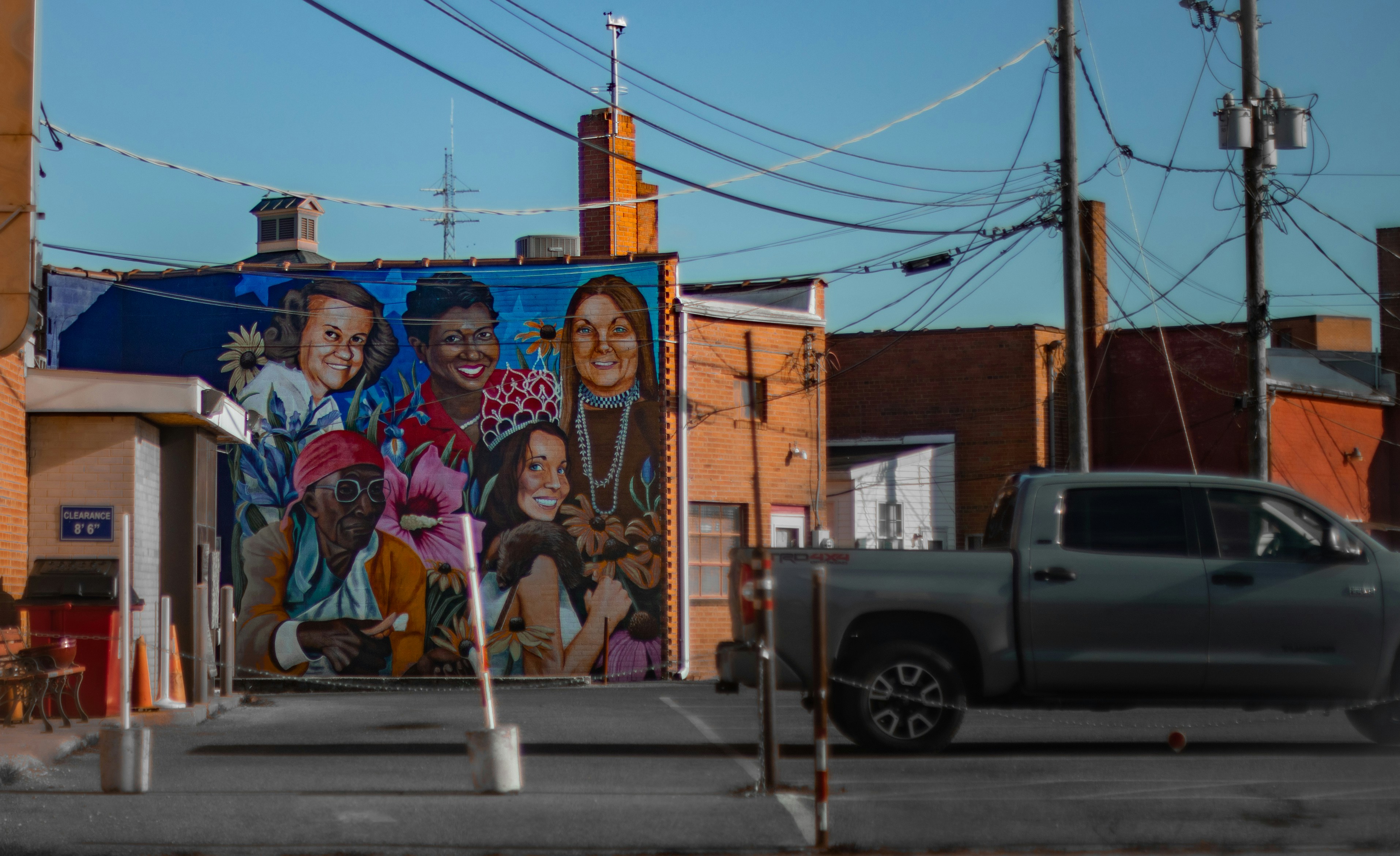 Vibrant mural depicting diverse individuals showcasing community spirit and unity. The artwork adorns a brick wall, surrounded by urban elements.