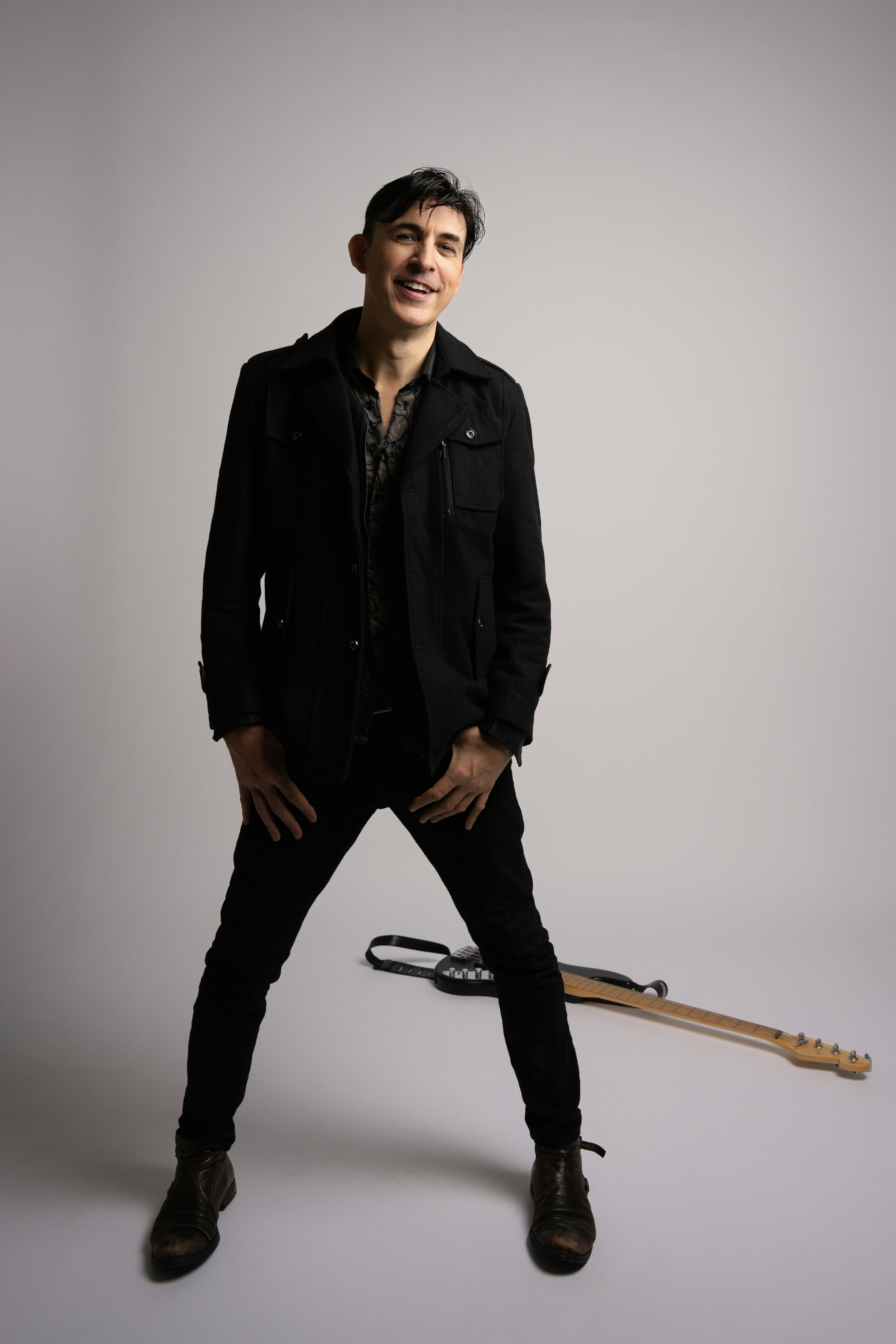 Black Denim, Quiet Stage: Studio Portrait with a Guitar at Rest
