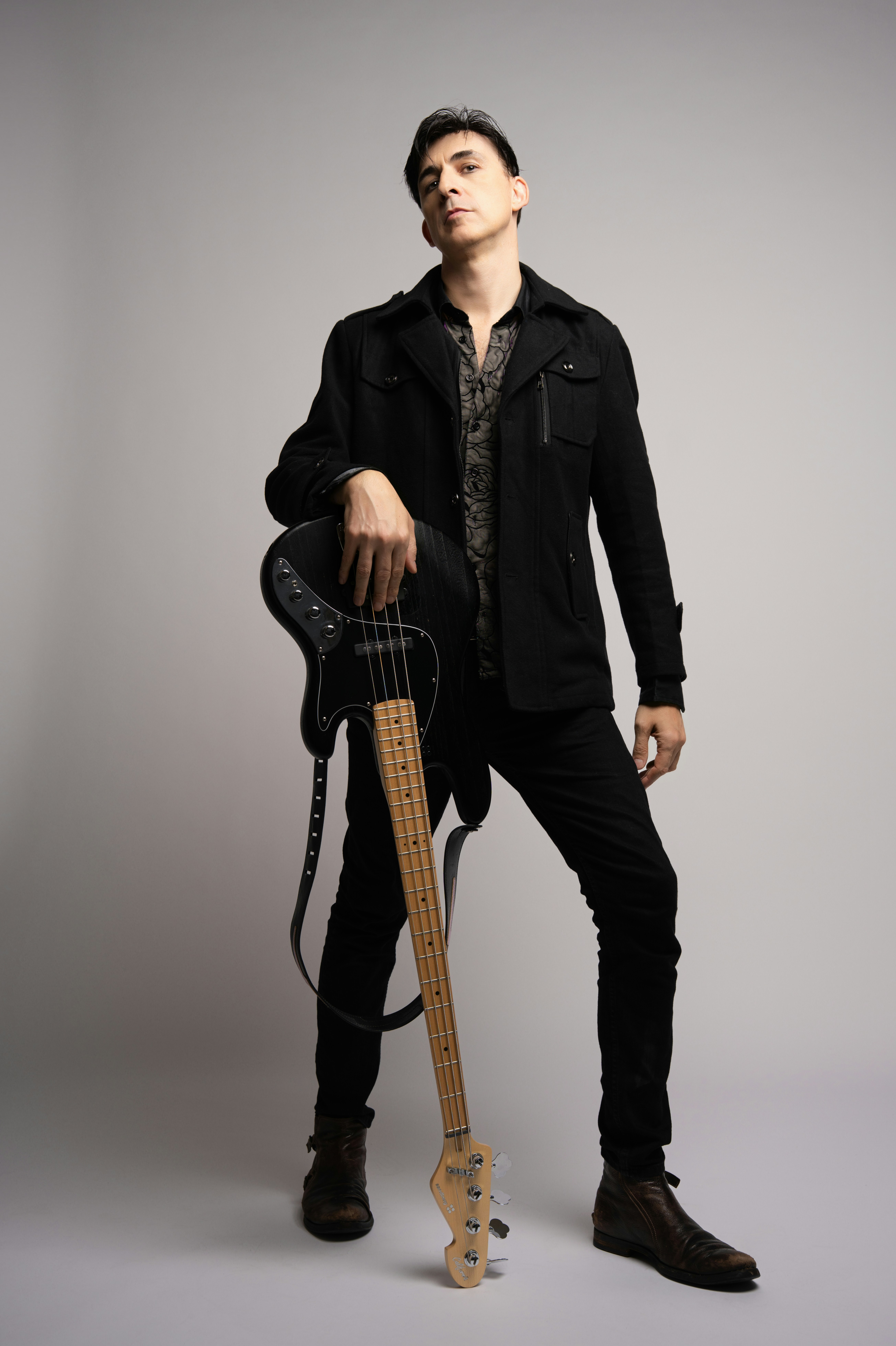 Noir Reverie: A guitarist anchors a black electric guitar in a stark studio portrait