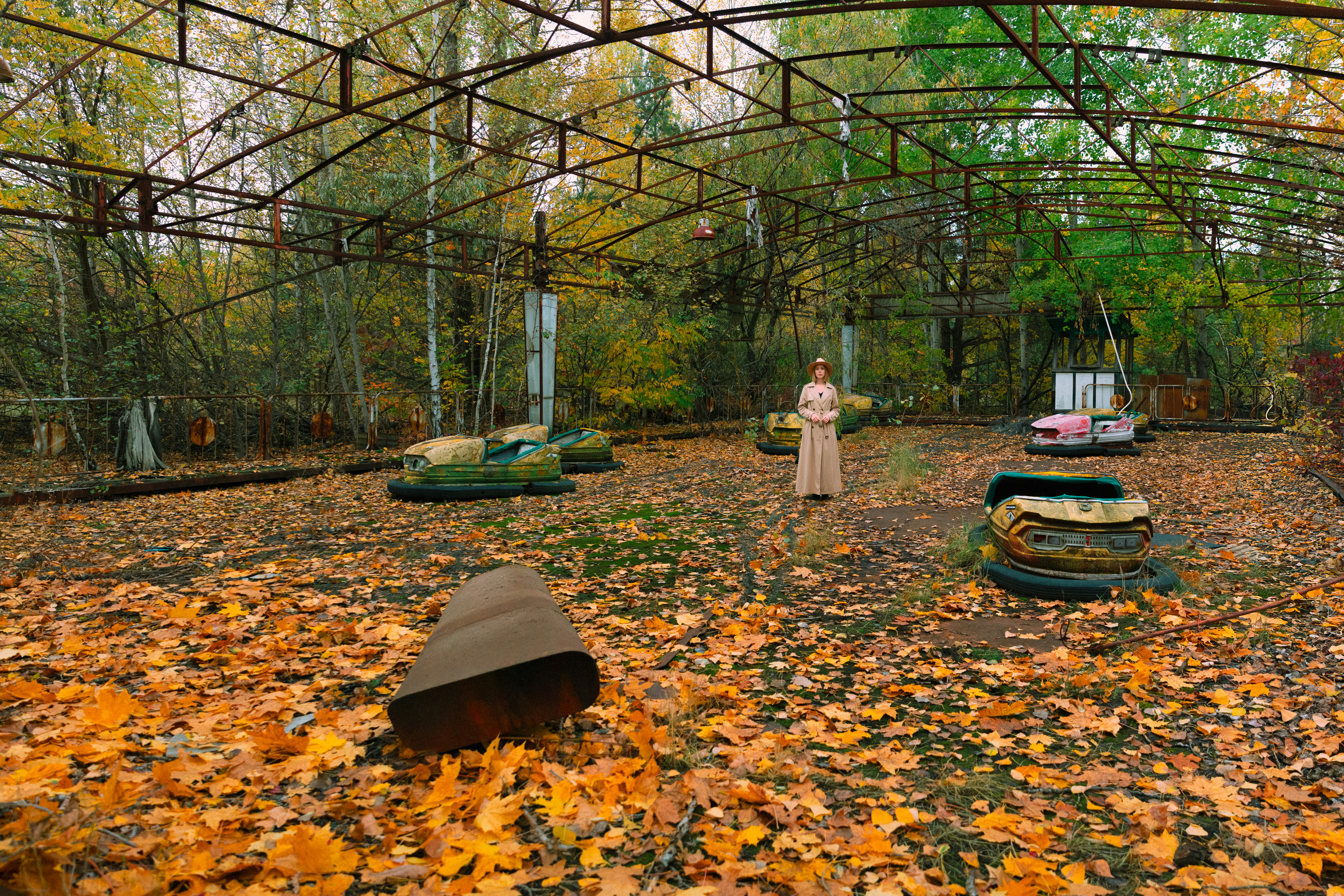 Person stands in abandoned amusement park with autumn leaves