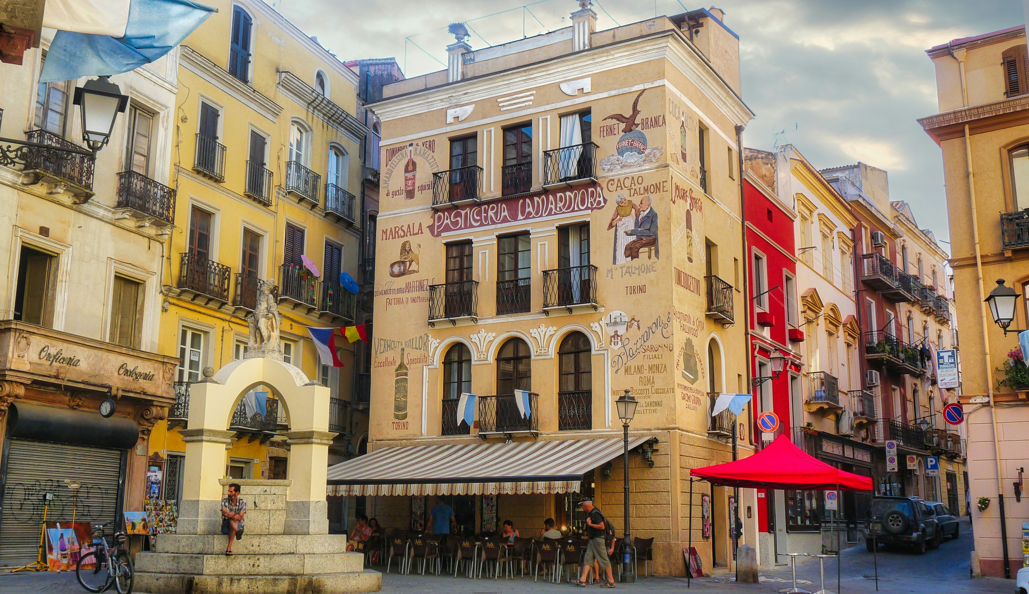 Historic building adorned with vibrant murals showcasing local cuisine, surrounded by charming streets and outdoor dining. A lively atmosphere invites exploration.