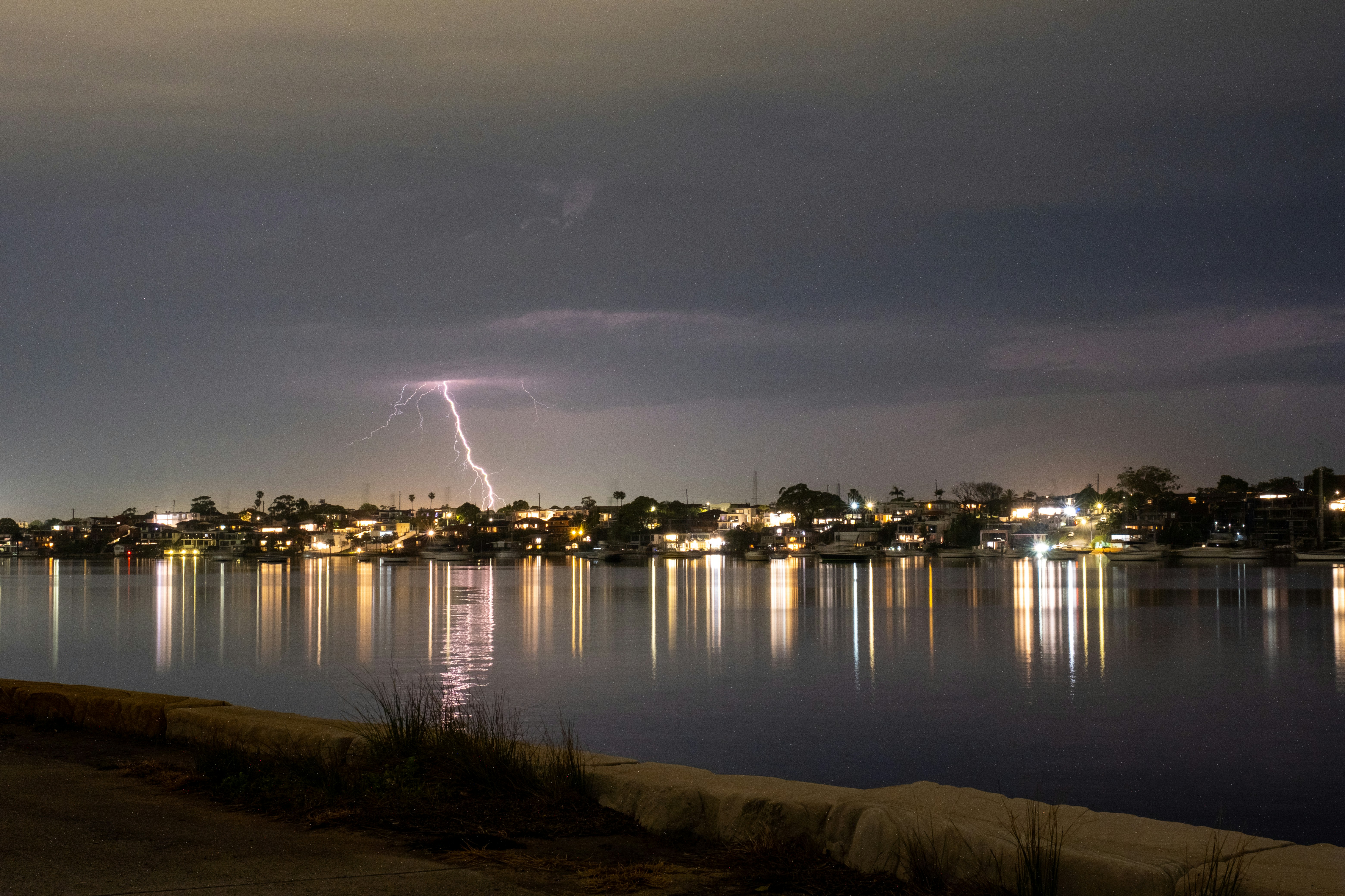 Bolt Over the Harbor: Neon Ripples Ignite a Thunderlit Night