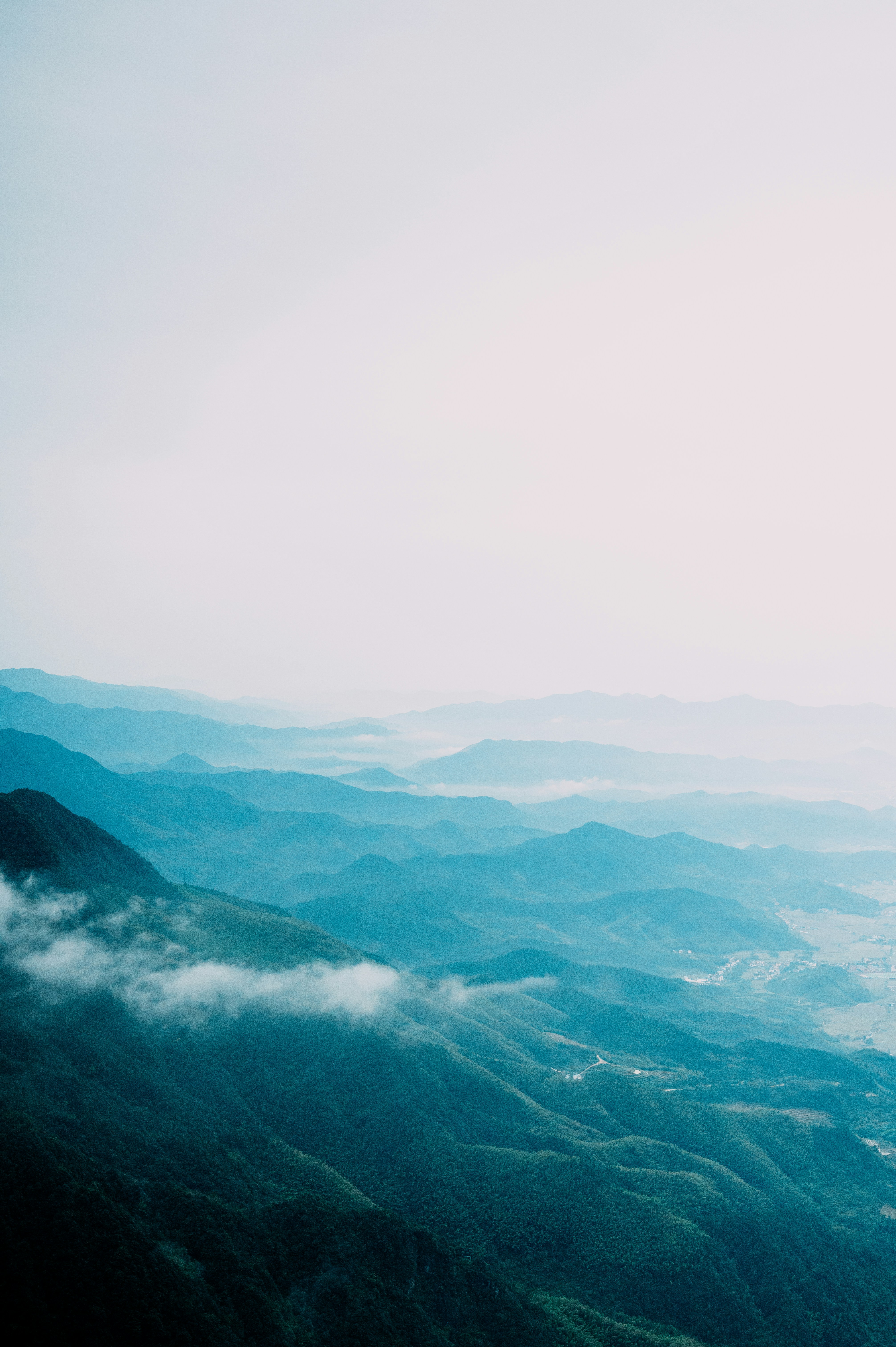 Layered mountains shrouded in mist, fading into the horizon under a pale sky.