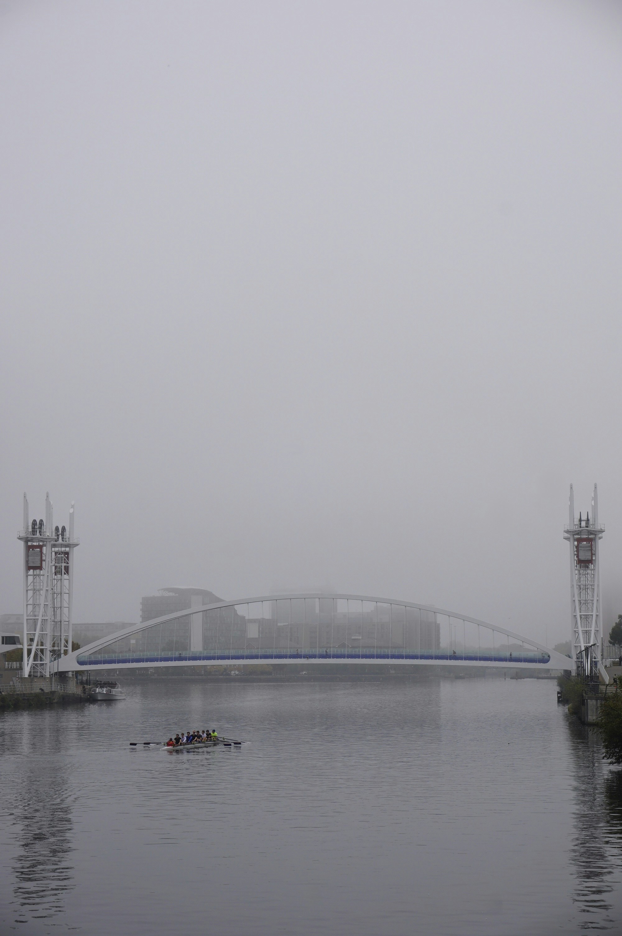 Rowers in the Mist Beneath a Silent Arc Bridge