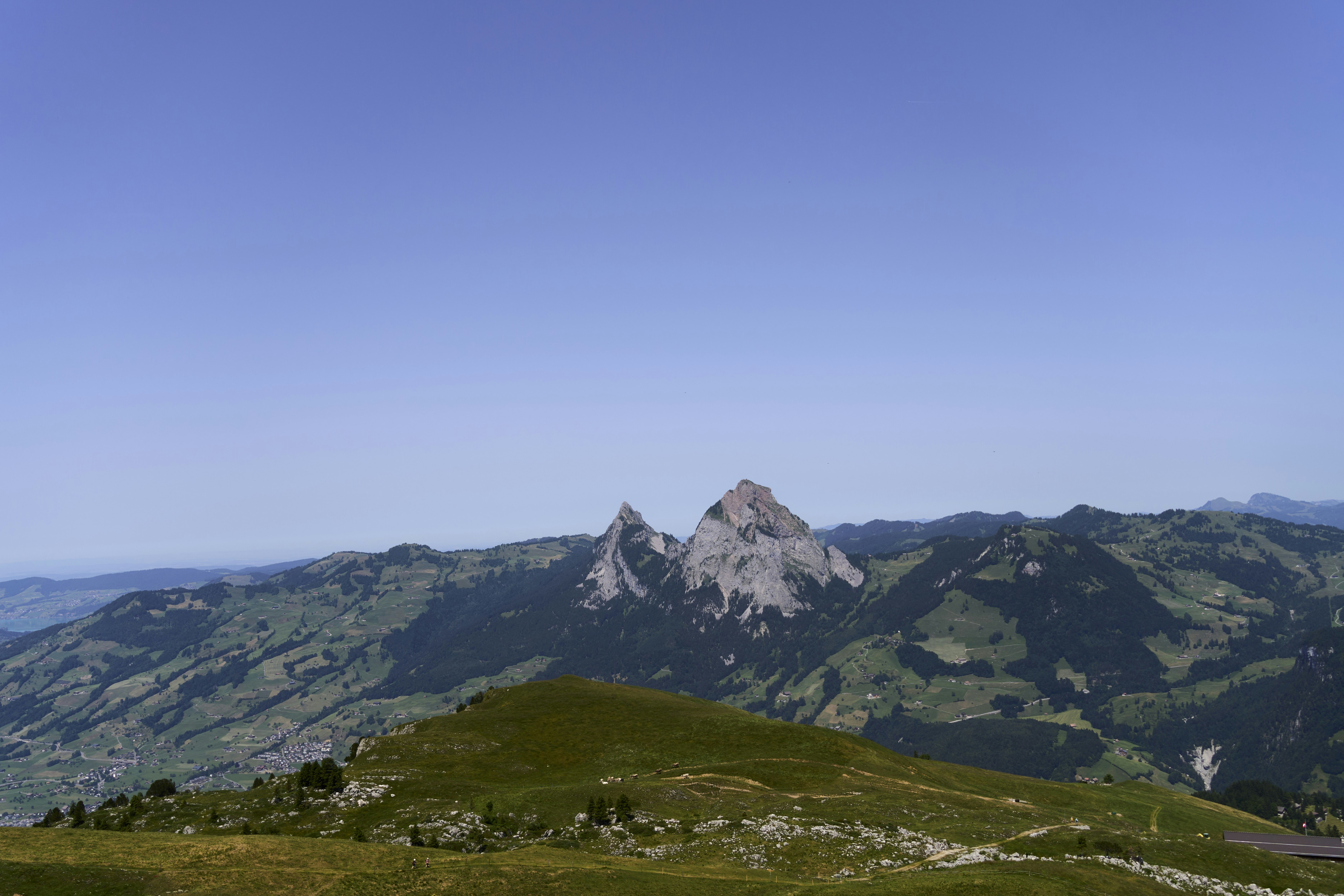Jagged mountain peaks rise above green rolling hills.