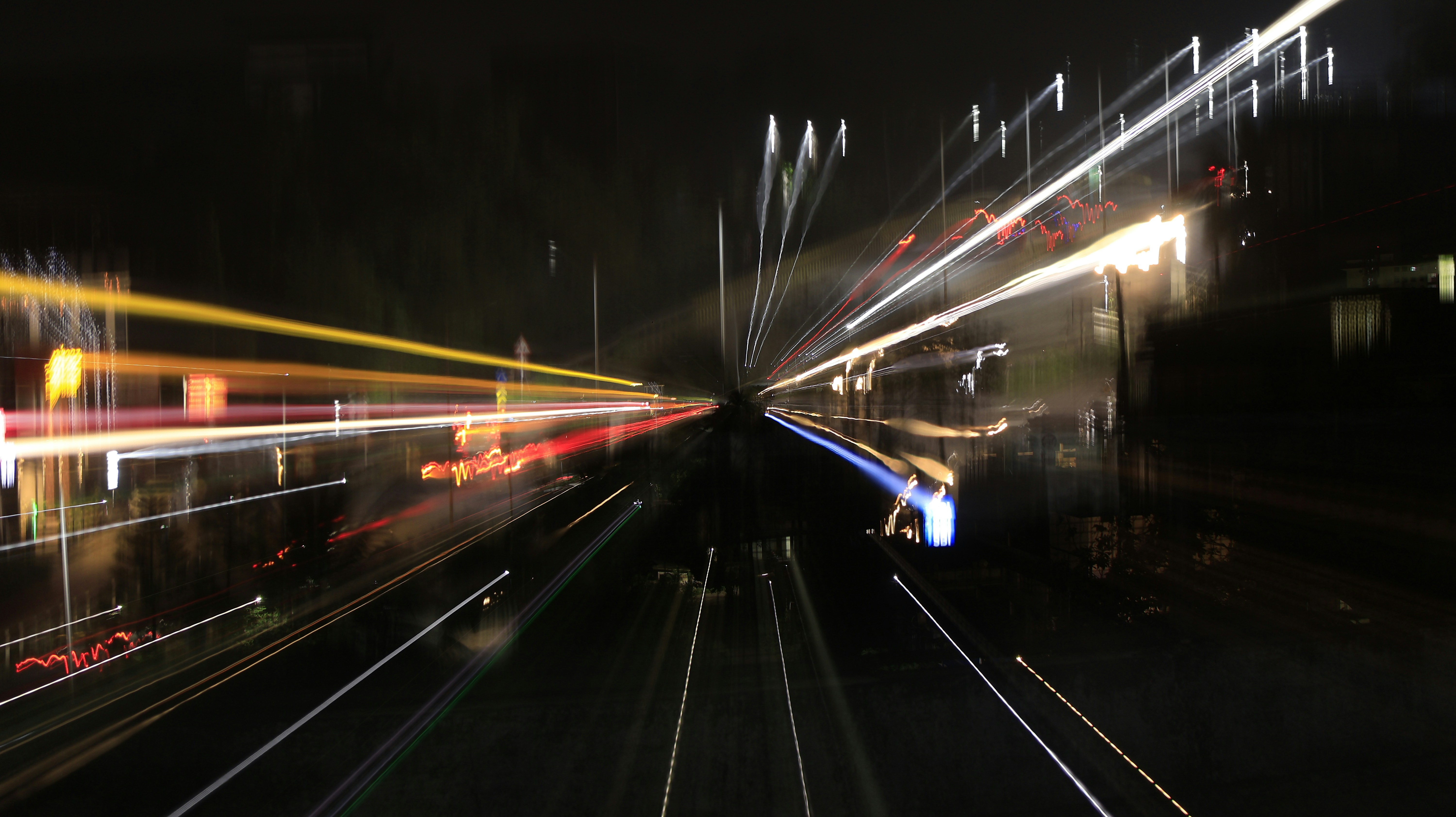 Dynamic light trails from passing trains create a vibrant display of energy and motion against a dark backdrop.