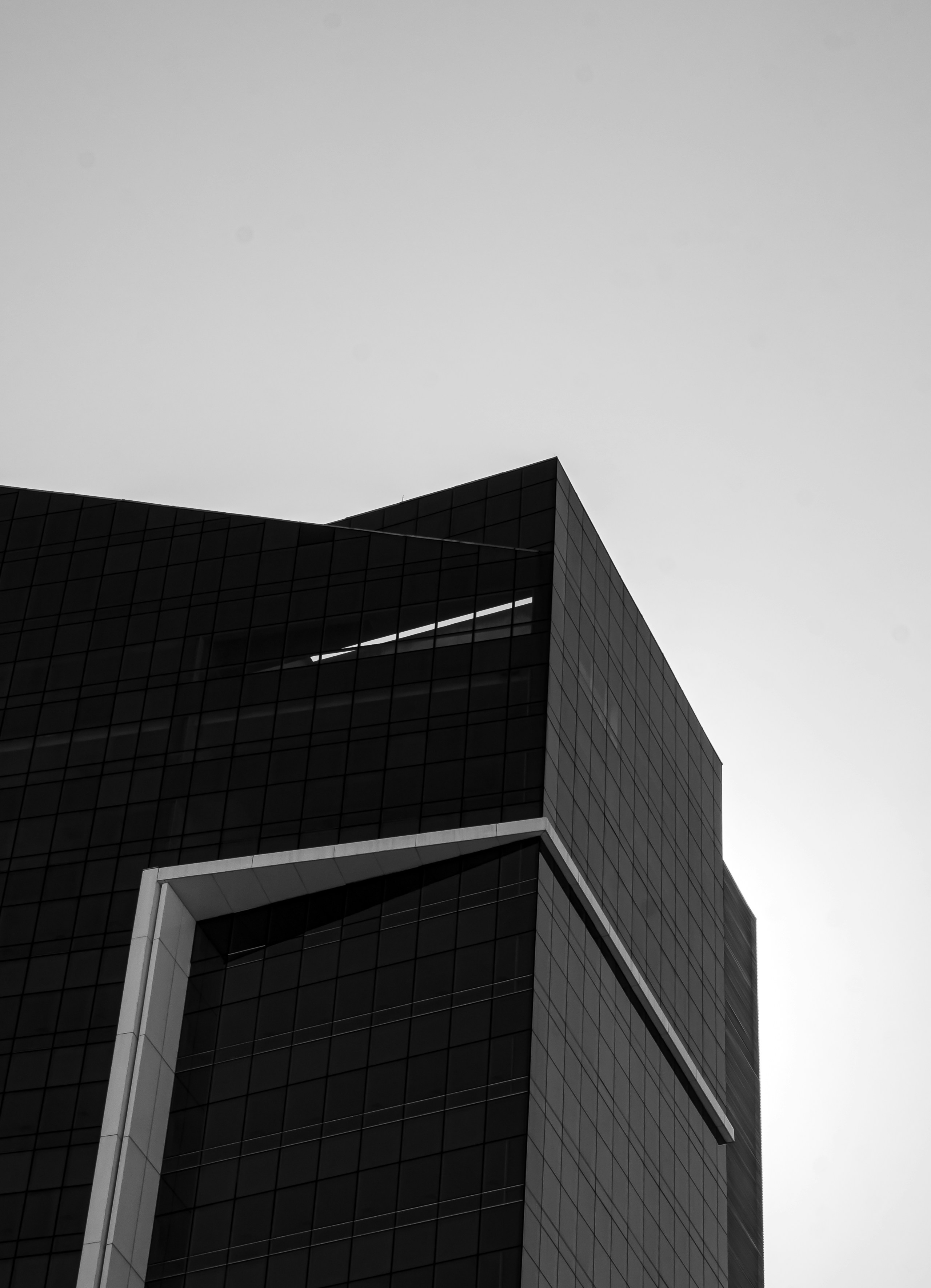 Angular black and white architectural composition showcasing a modern building's sharp edges and reflective surfaces.